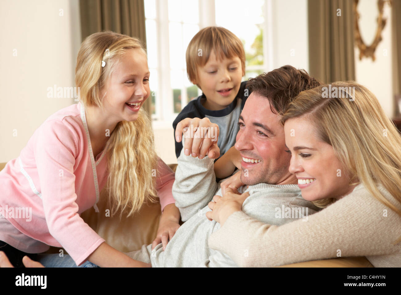 Happy young family playing together on sofa Stock Photo - Alamy