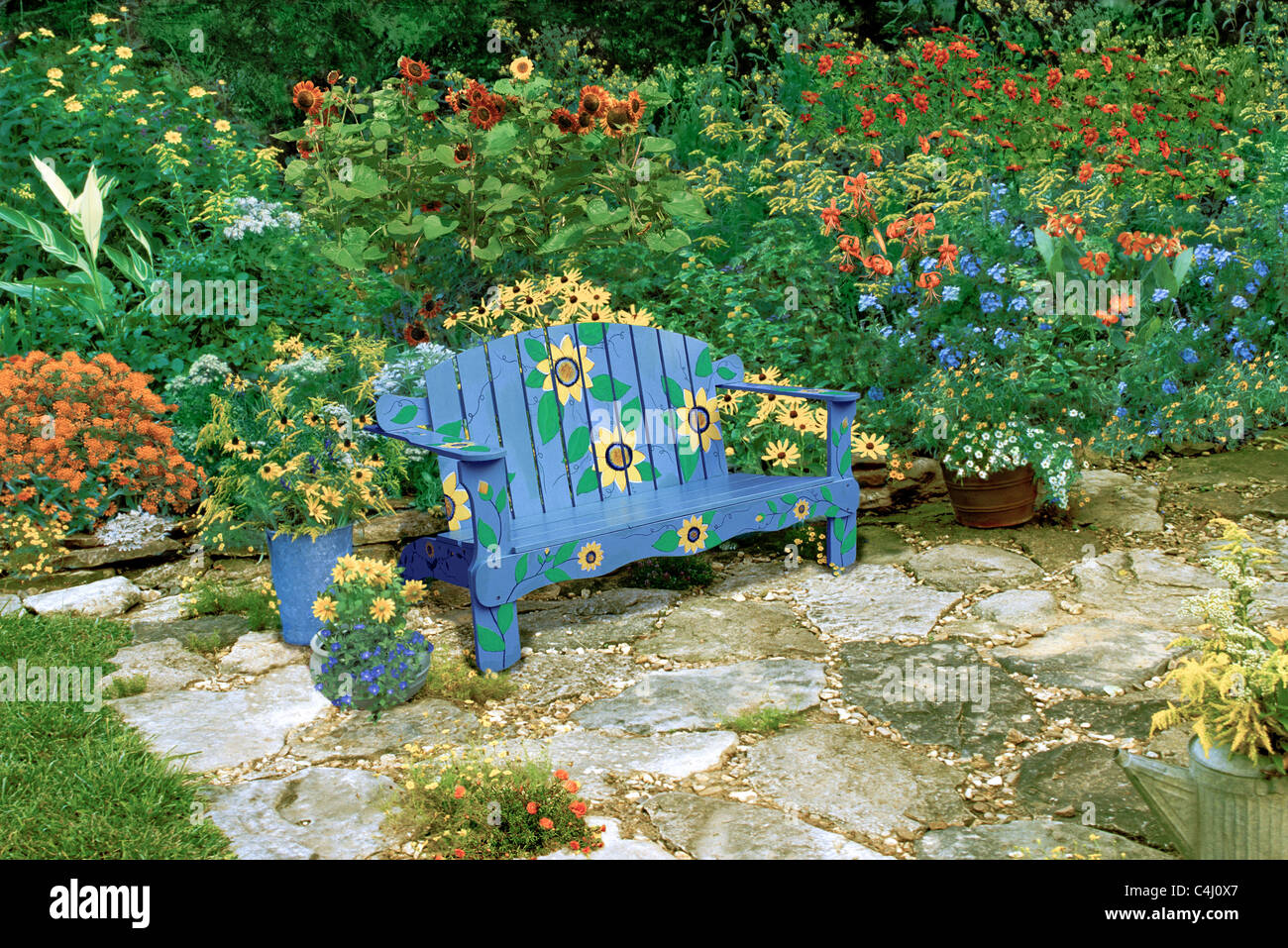 Blue bench painted with sunflowers sits in the garden patio of stone ...