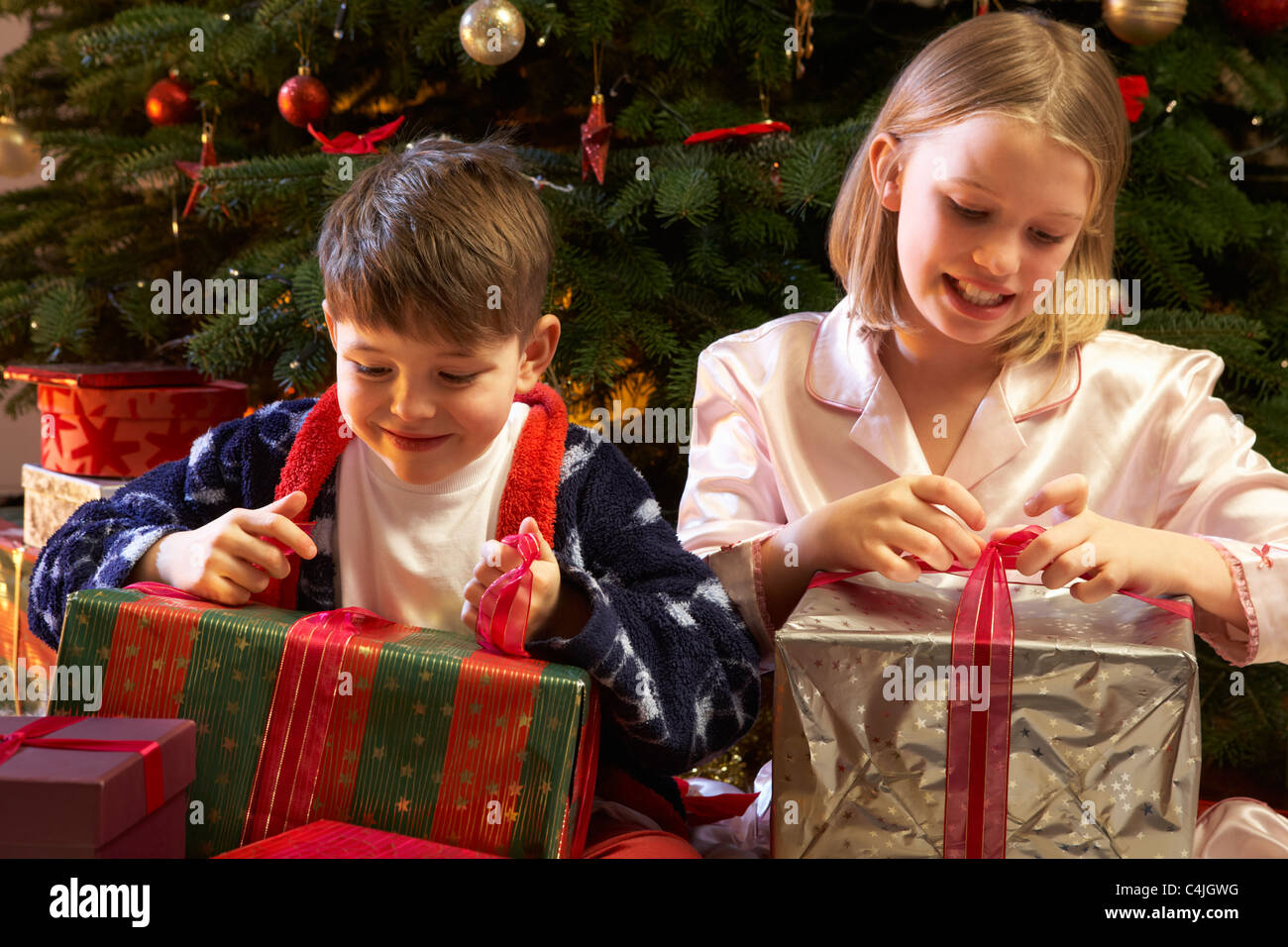 Children Opening Christmas Present In Front Of Tree Stock Photo - Alamy