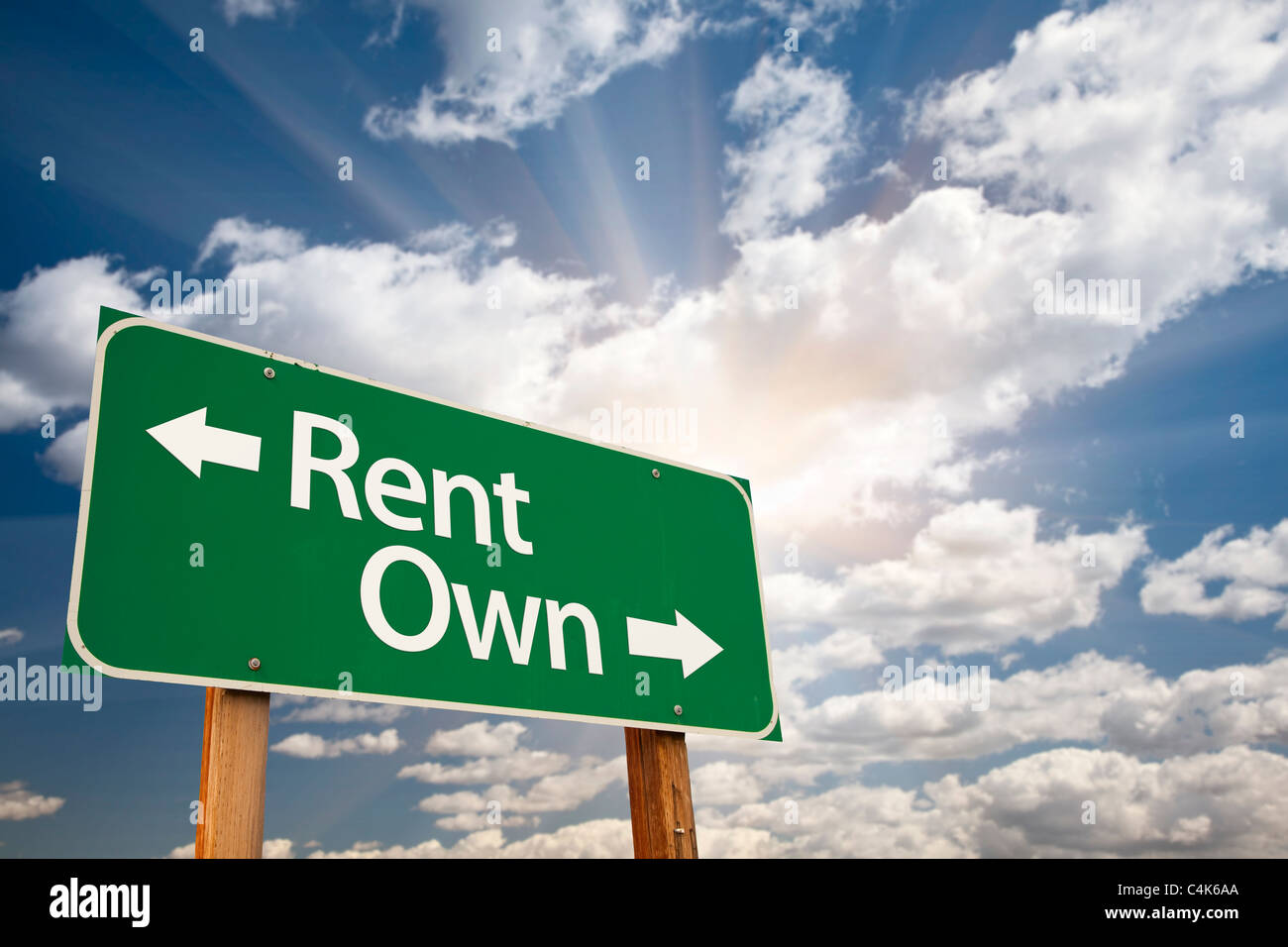 Rent, Own Green Road Sign Against Clouds and Sunburst Stock Photo - Alamy