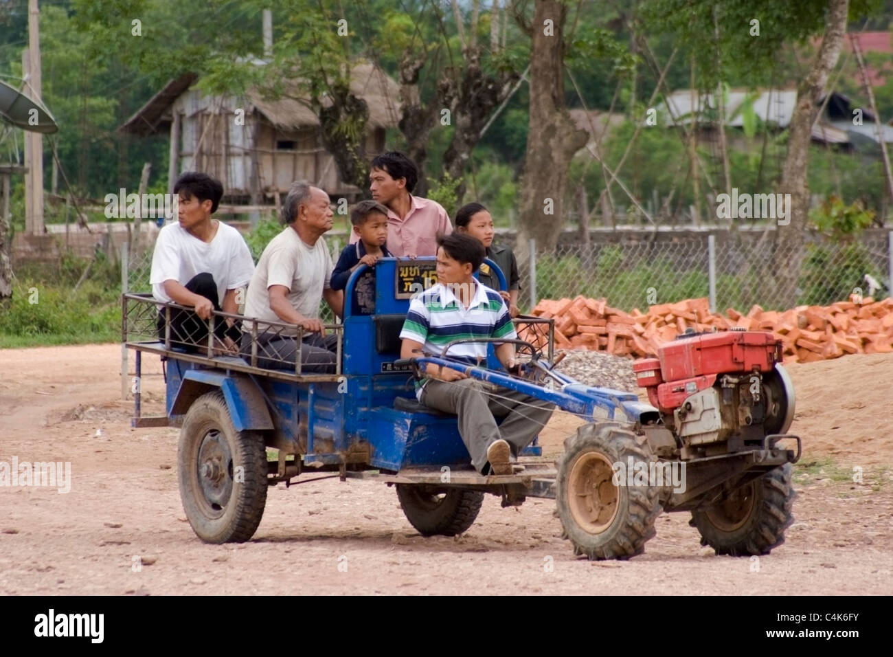 A group of subsistence farmers are riding on a tractor in rural ...