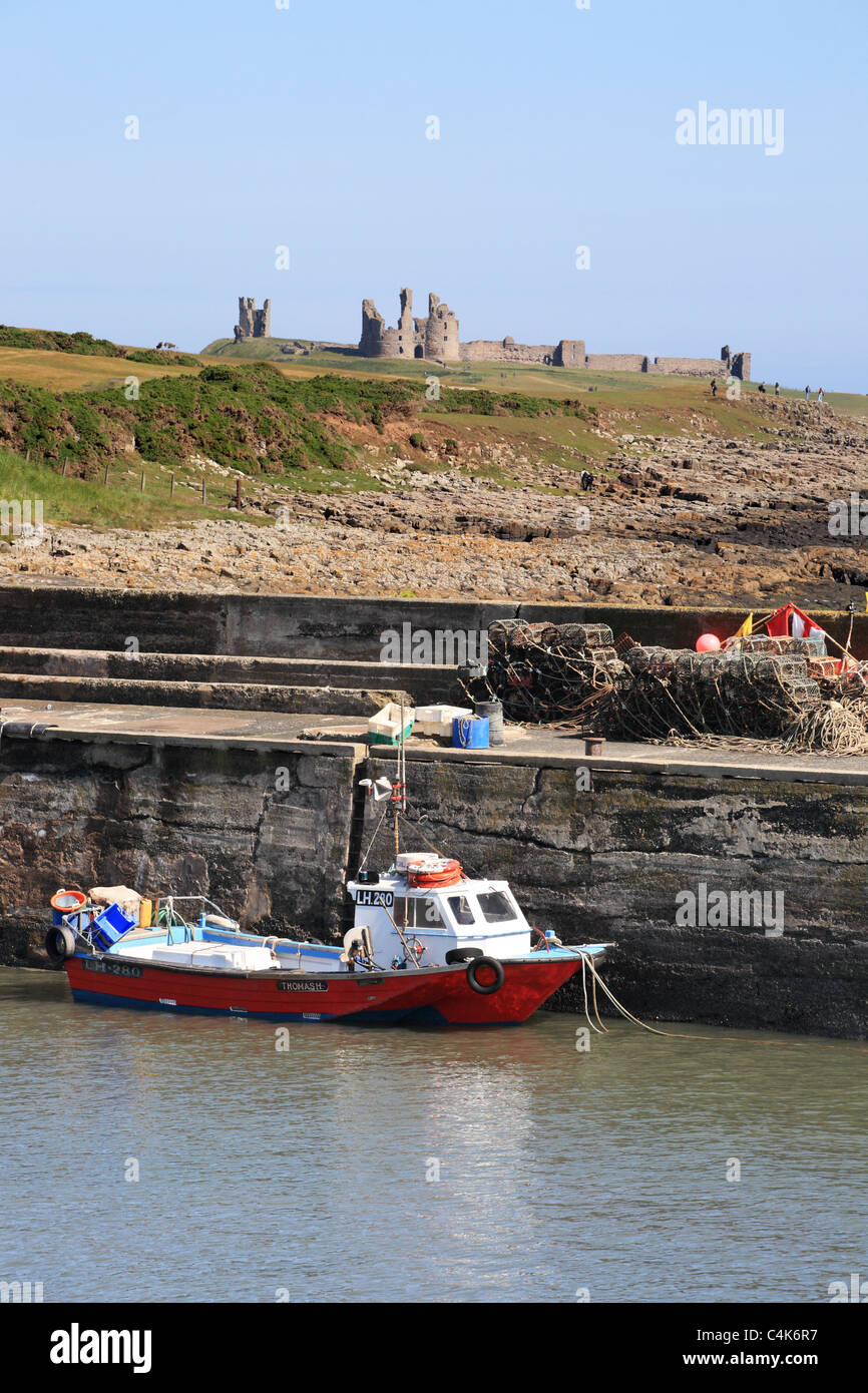 Fishing boat in Craster harbour with Dunstanburgh castle in the ...