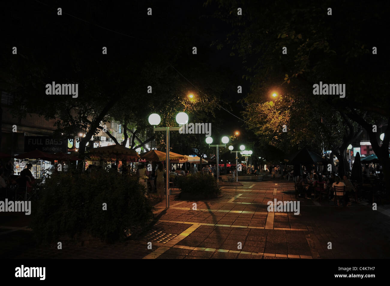 Night-time view pedestrian street, with line of central bushes and ...