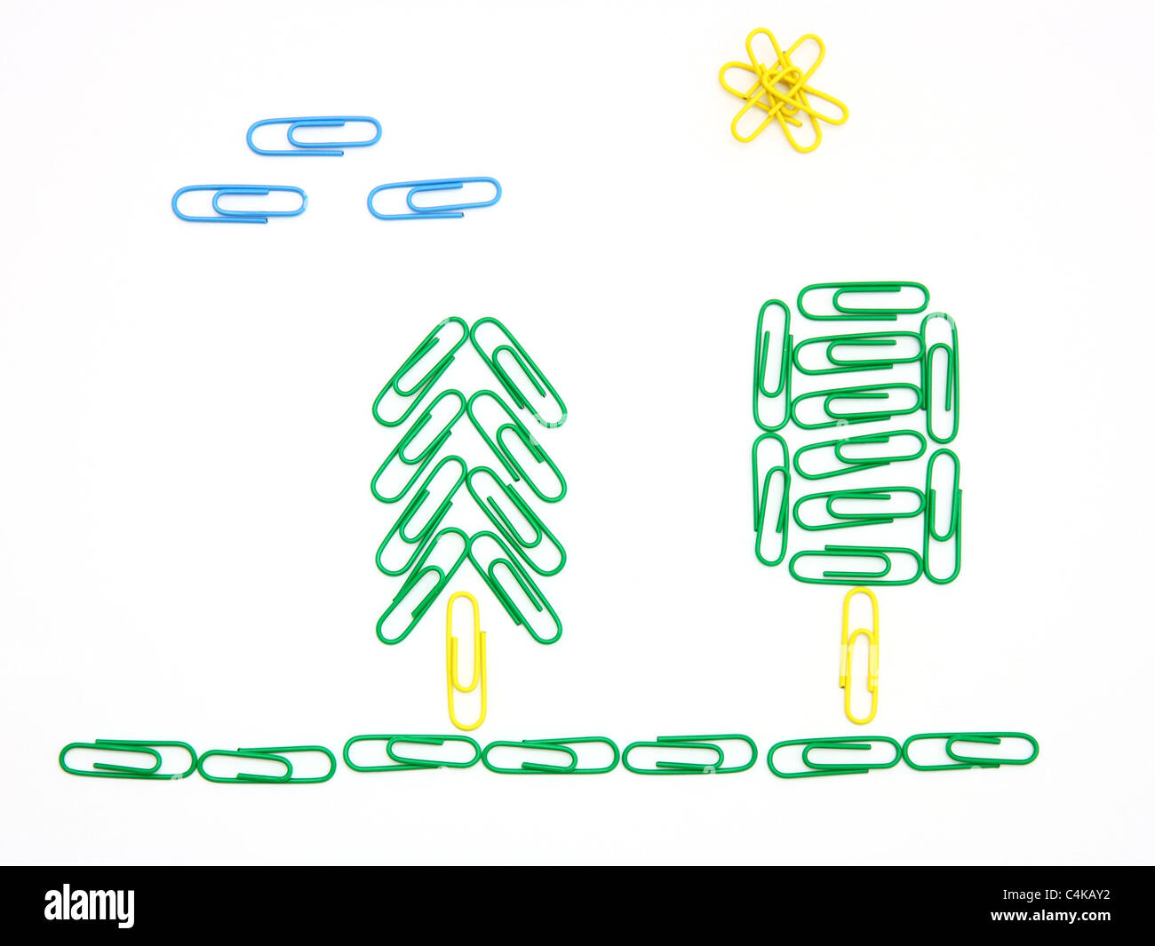 Trees from color paper clips on a white background with clouds and the ...