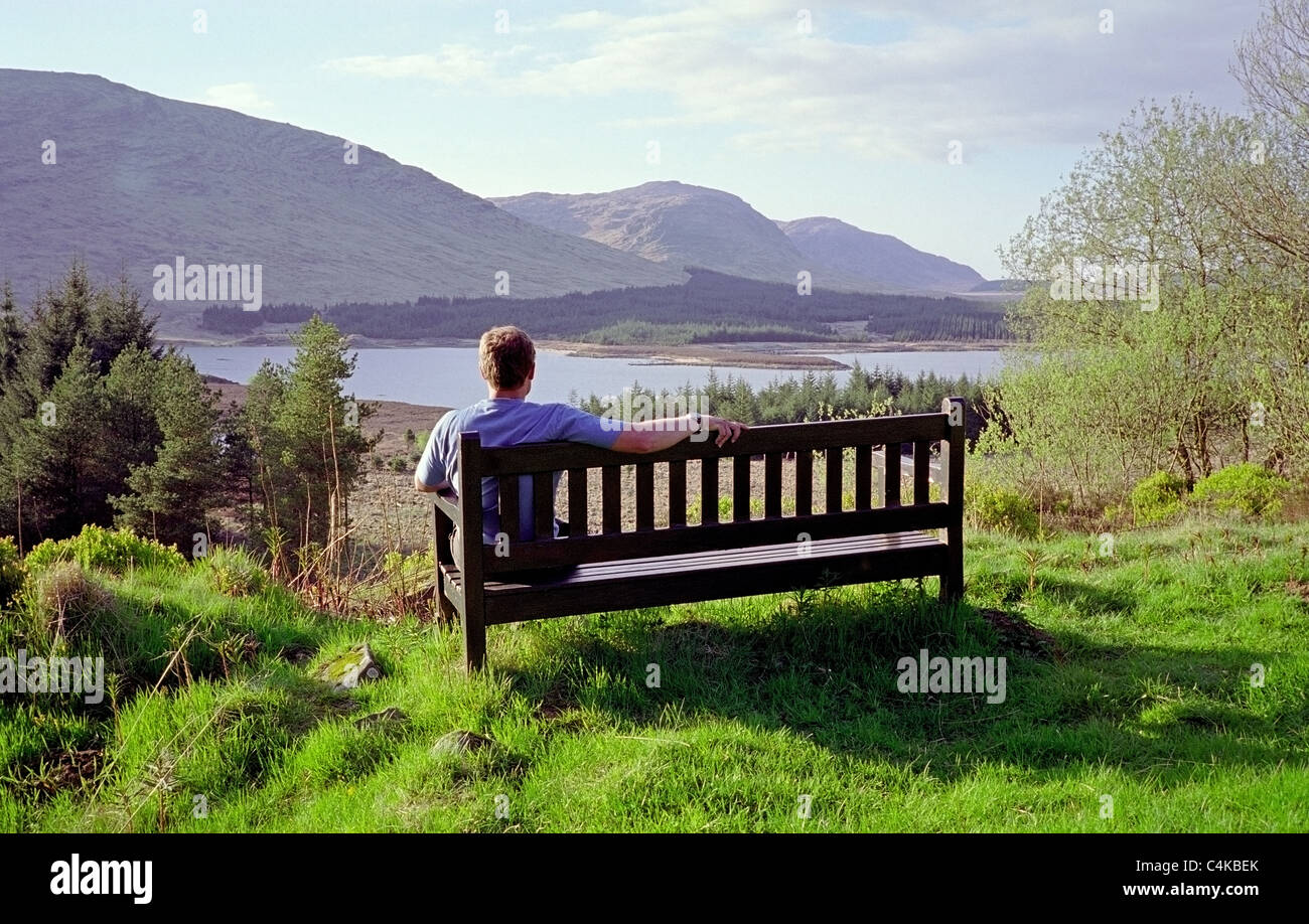 Caucasian Male sitting on a bench overlooking Loch Dee, Galloway Forest ...