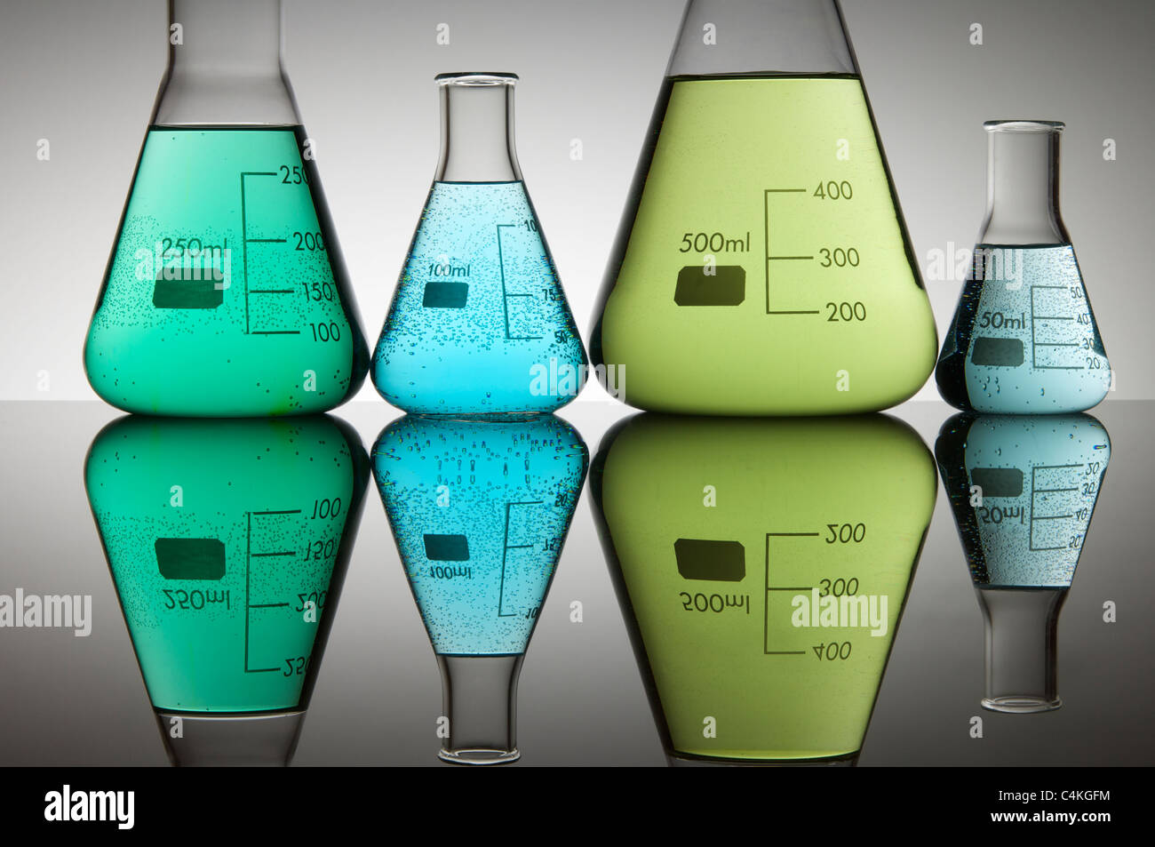 four conical flasks with green and blue liquid with a white background ...