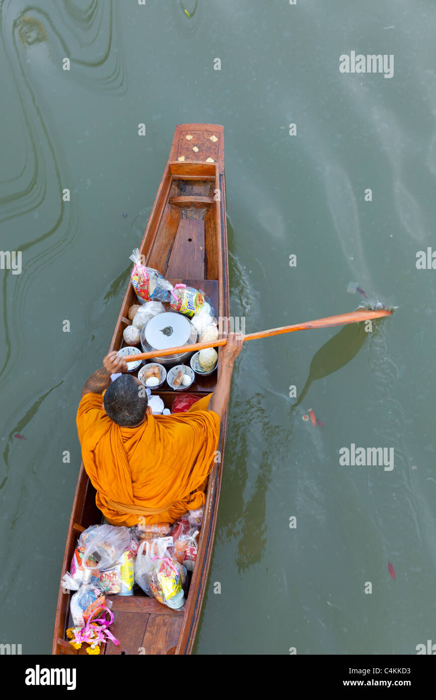 Thai buddhist monk rowing boat early in the morning at amphawa floating ...