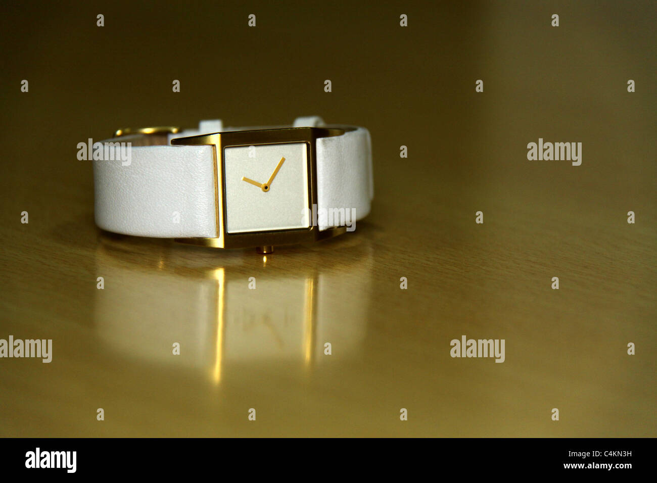 White and golden colored watch on wooden surface with reflection Stock ...
