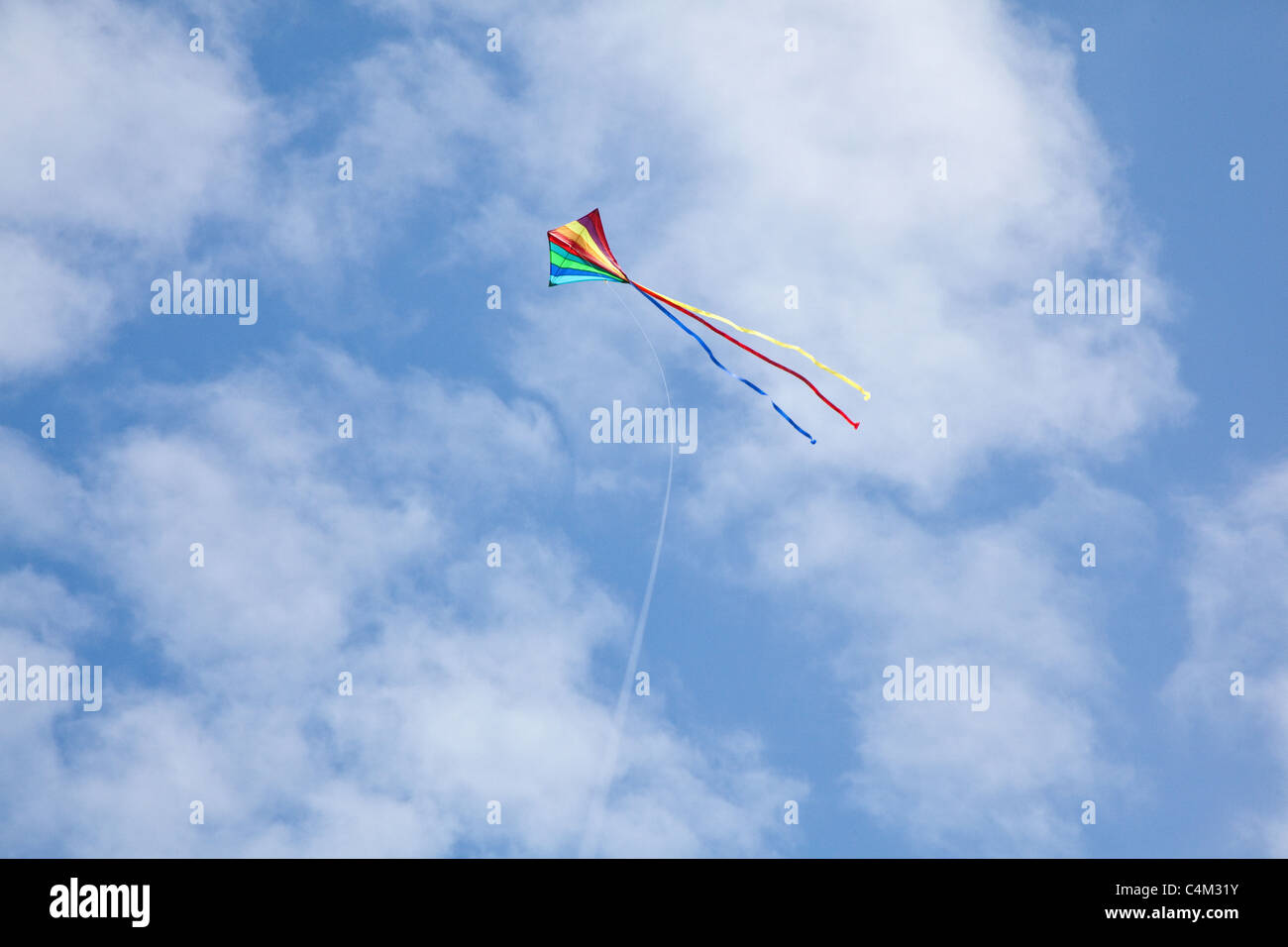 Rainbow kite flying on a string with a blue cloudy sky, Hampshire ...