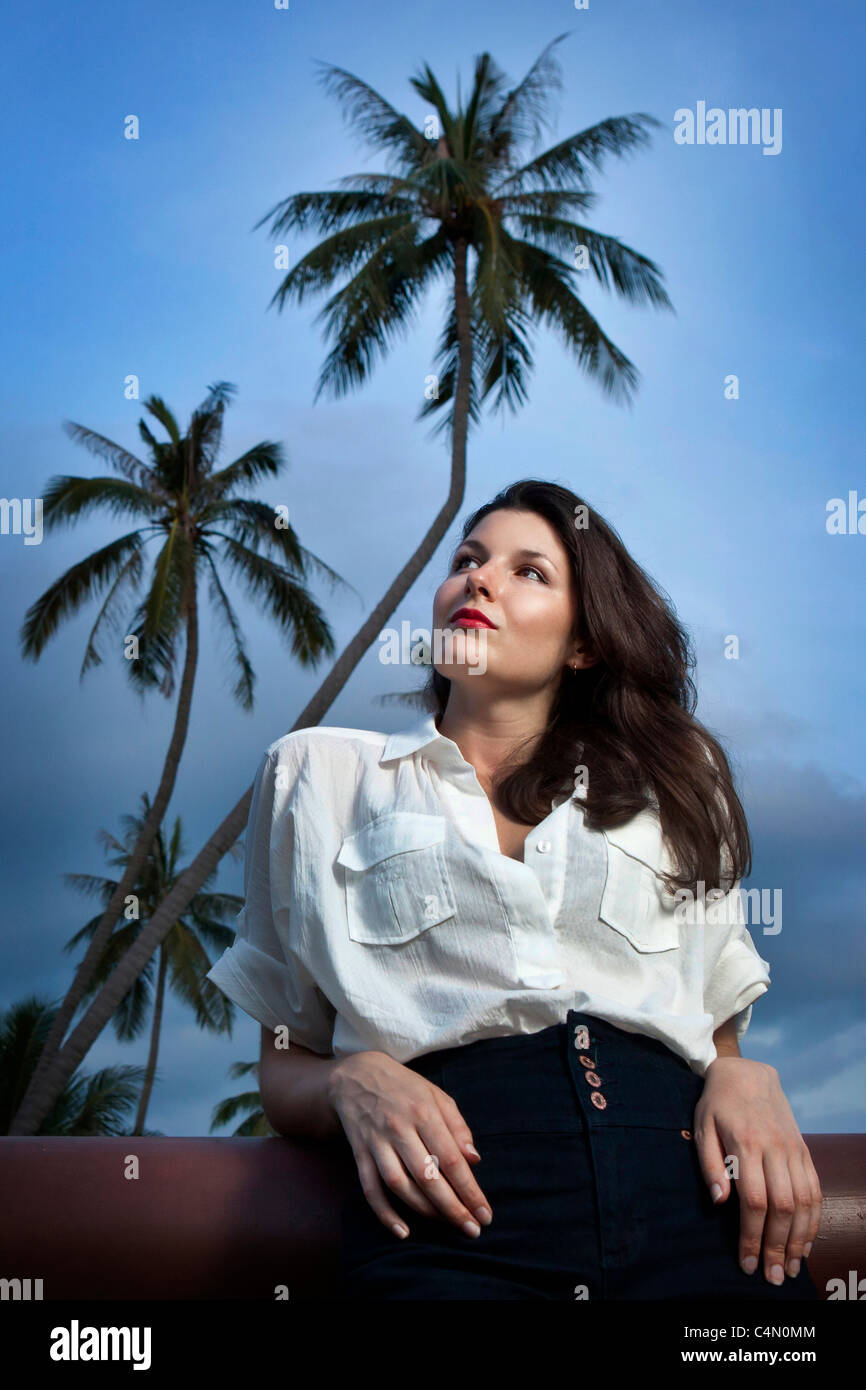 Portrait of a model leaning on a balcony in front of palm trees Stock ...