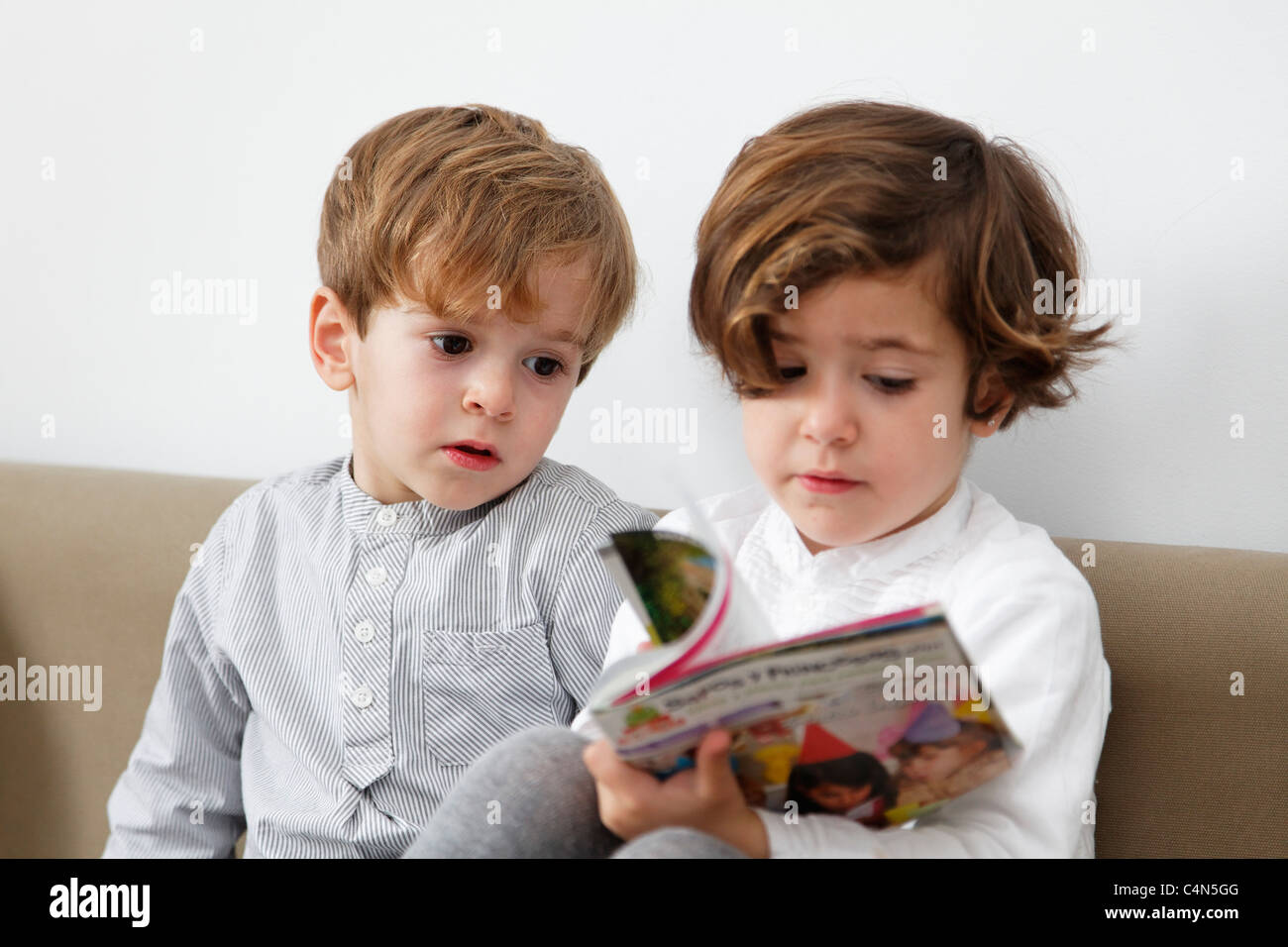 Two young children read a magazine Stock Photo - Alamy