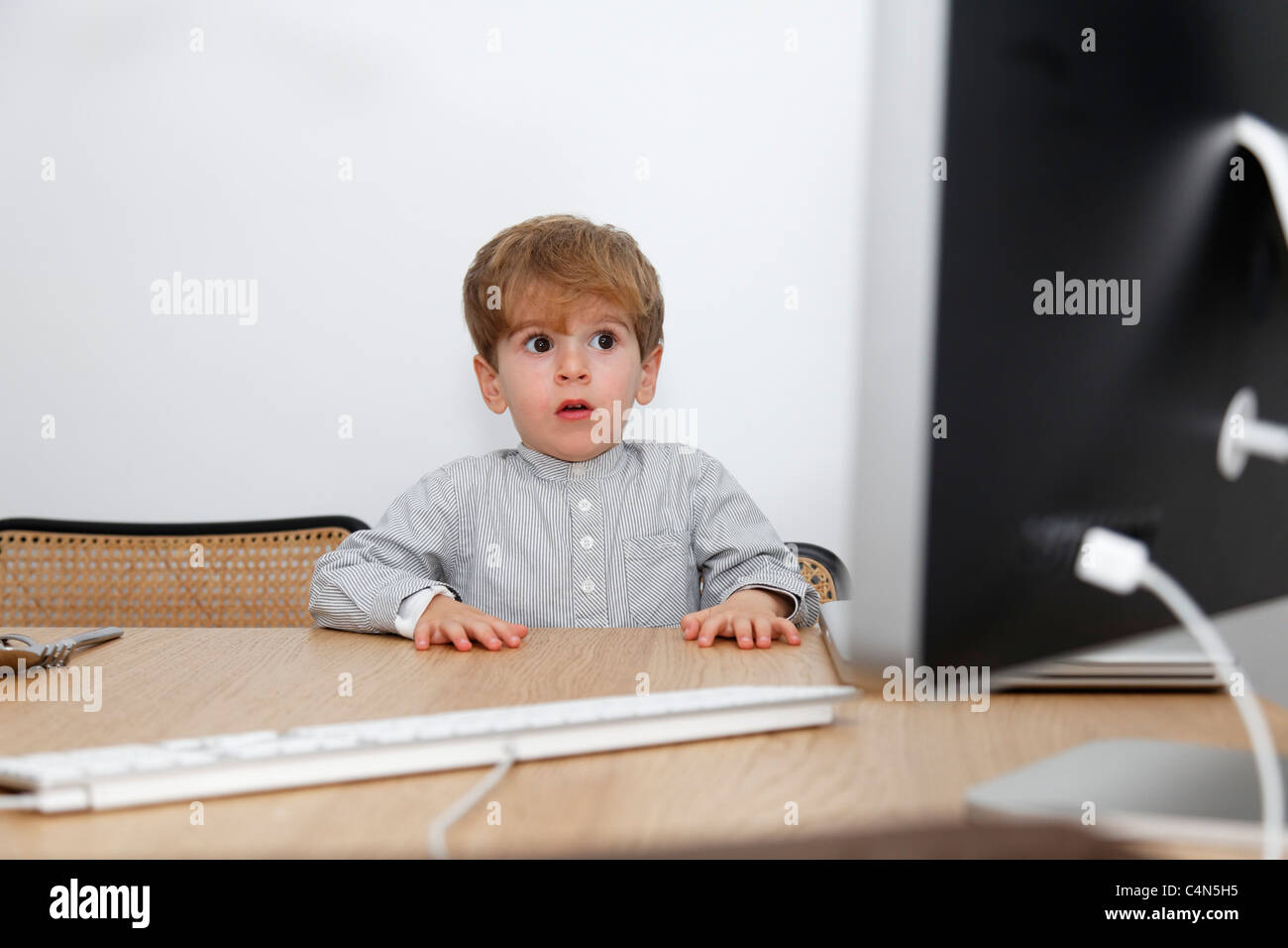Boy with startled expression looks at computer screen Stock Photo - Alamy