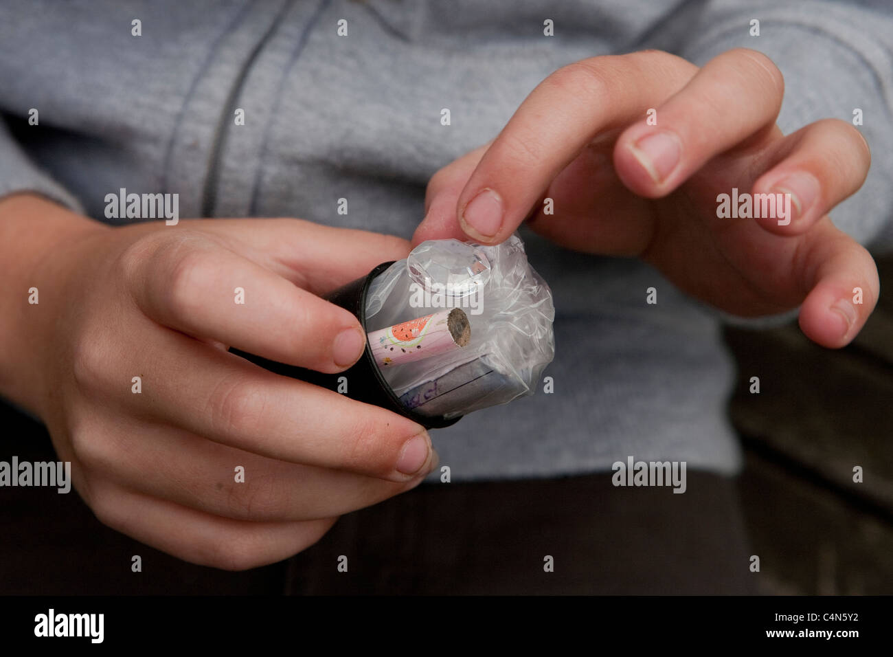 A boy examining the contents of a micro-cache Stock Photo - Alamy