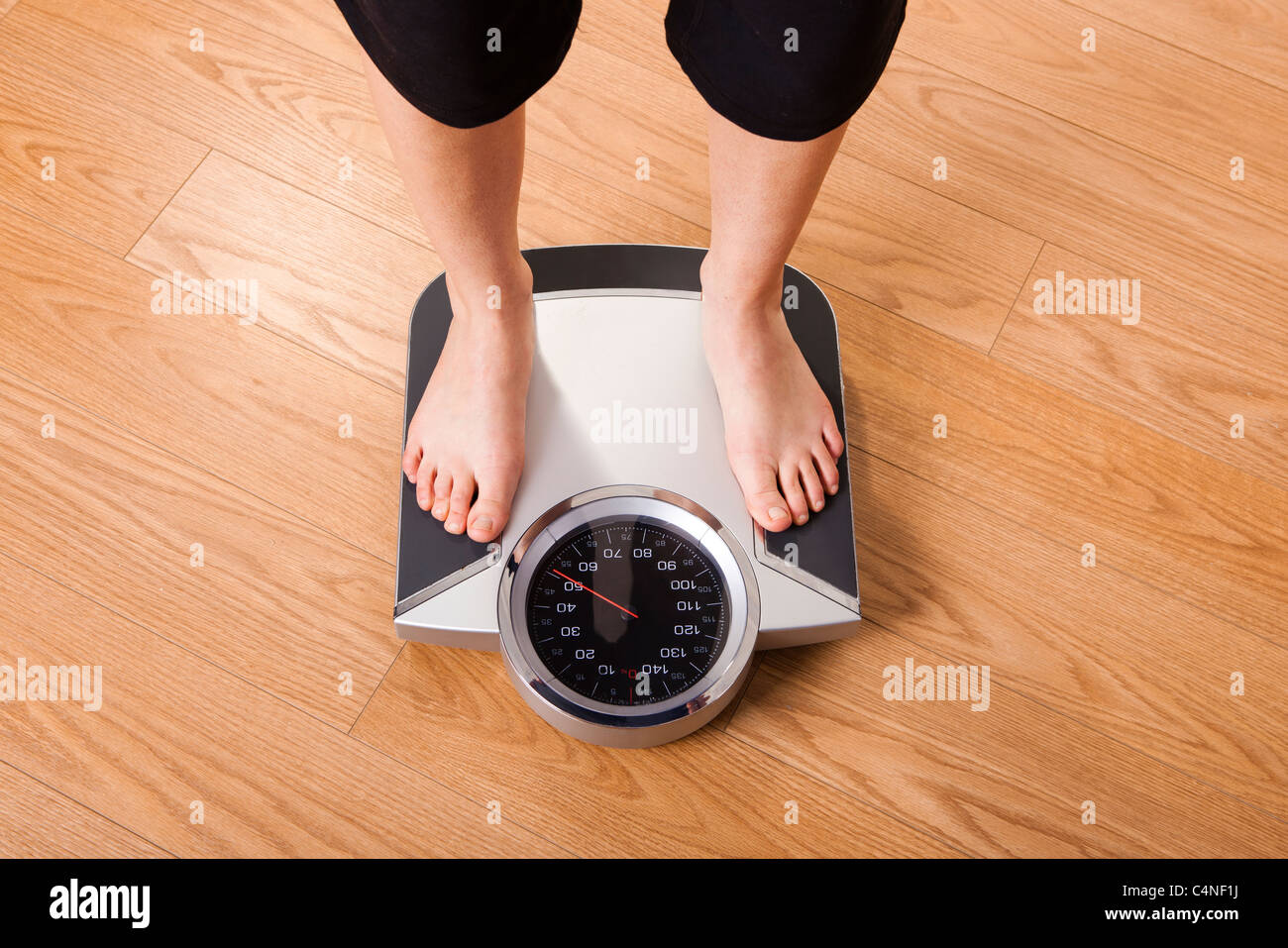 Athletic young girl measuring her weight on a scale Stock Photo - Alamy