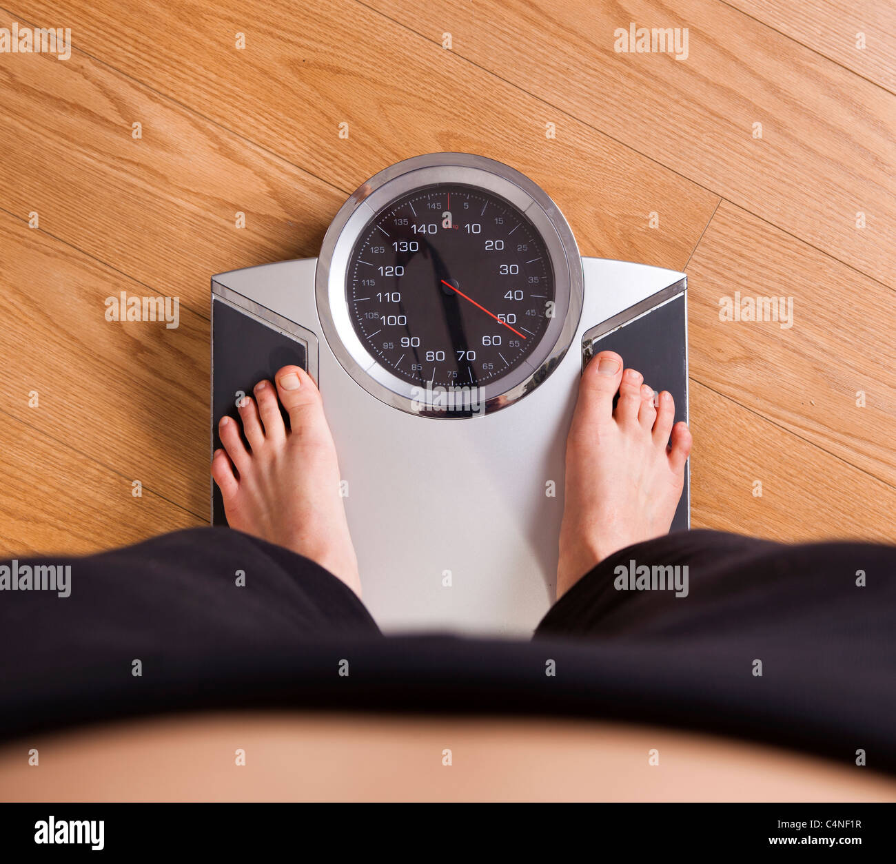 Athletic young girl measuring her weight on a scale Stock Photo - Alamy