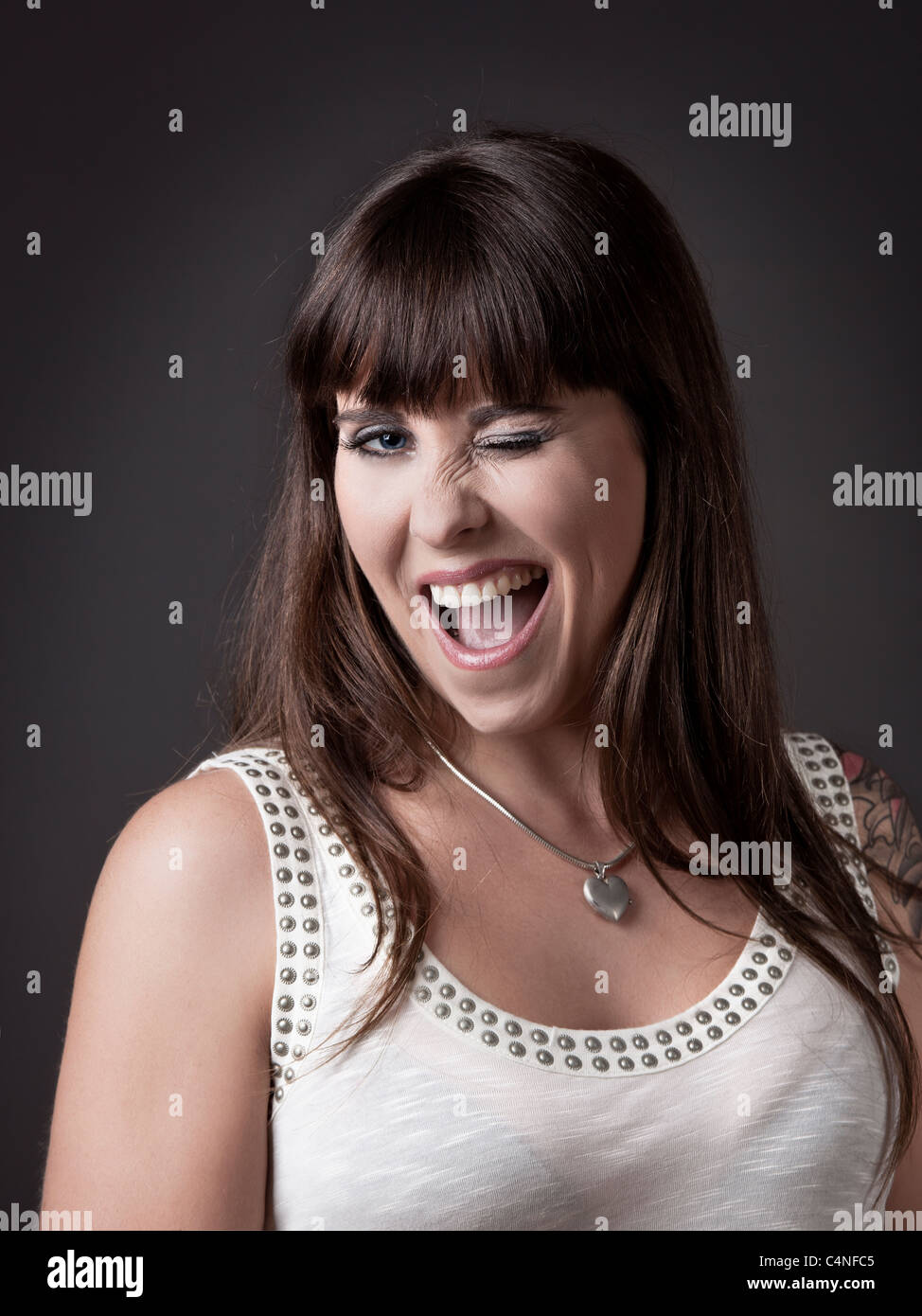 Beautiful young woman winking eyes against a grey background Stock ...