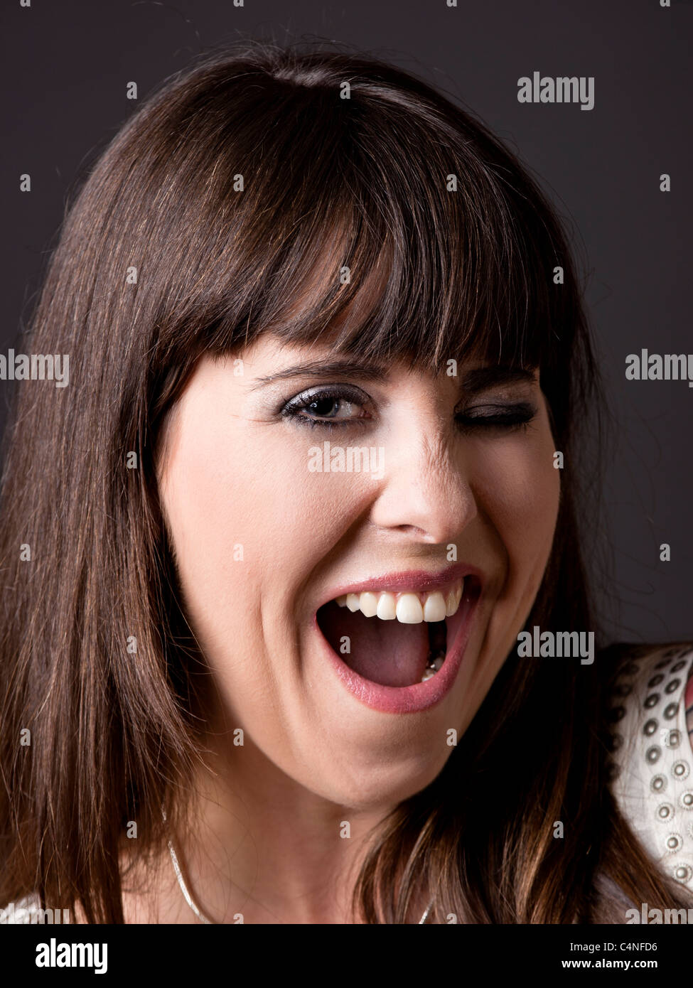 Beautiful young woman winking eyes, over a gray background Stock Photo ...