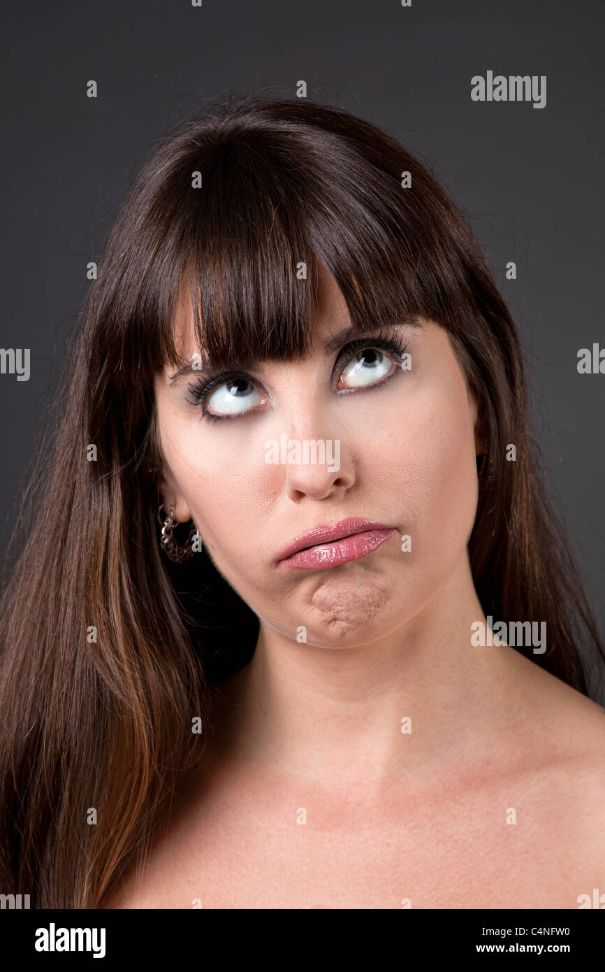 Portrait of a woman upset and thinking on something, against a grey ...