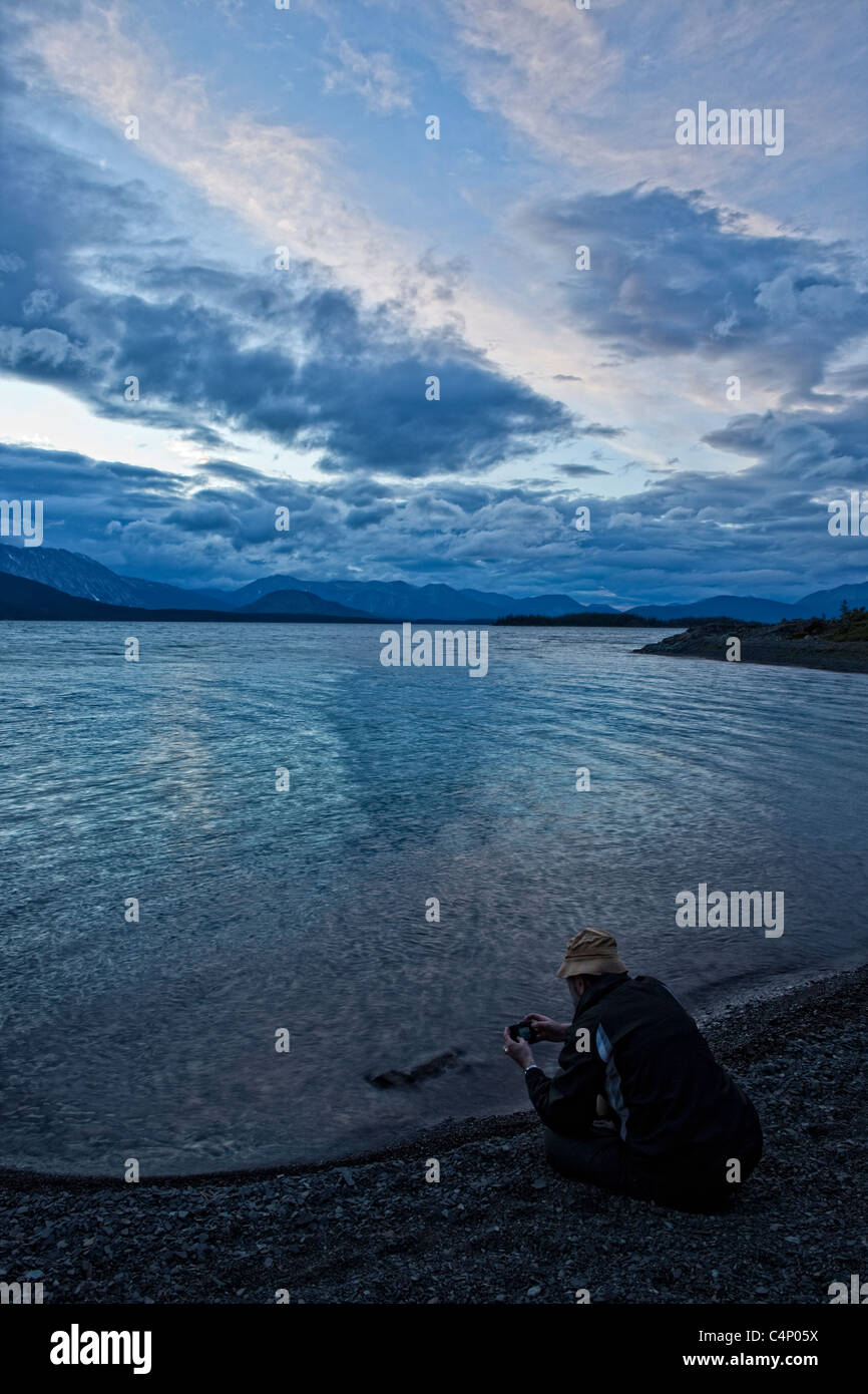 Person taking a picture from the shore of Atlin Lake, Atlin Provincial ...