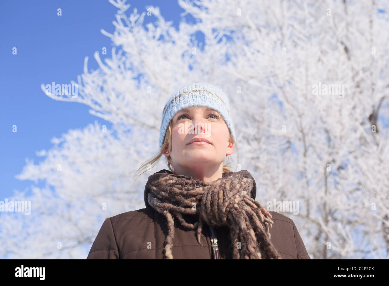Portrait of a woman outdoors in winter with frost-covered tree branches ...