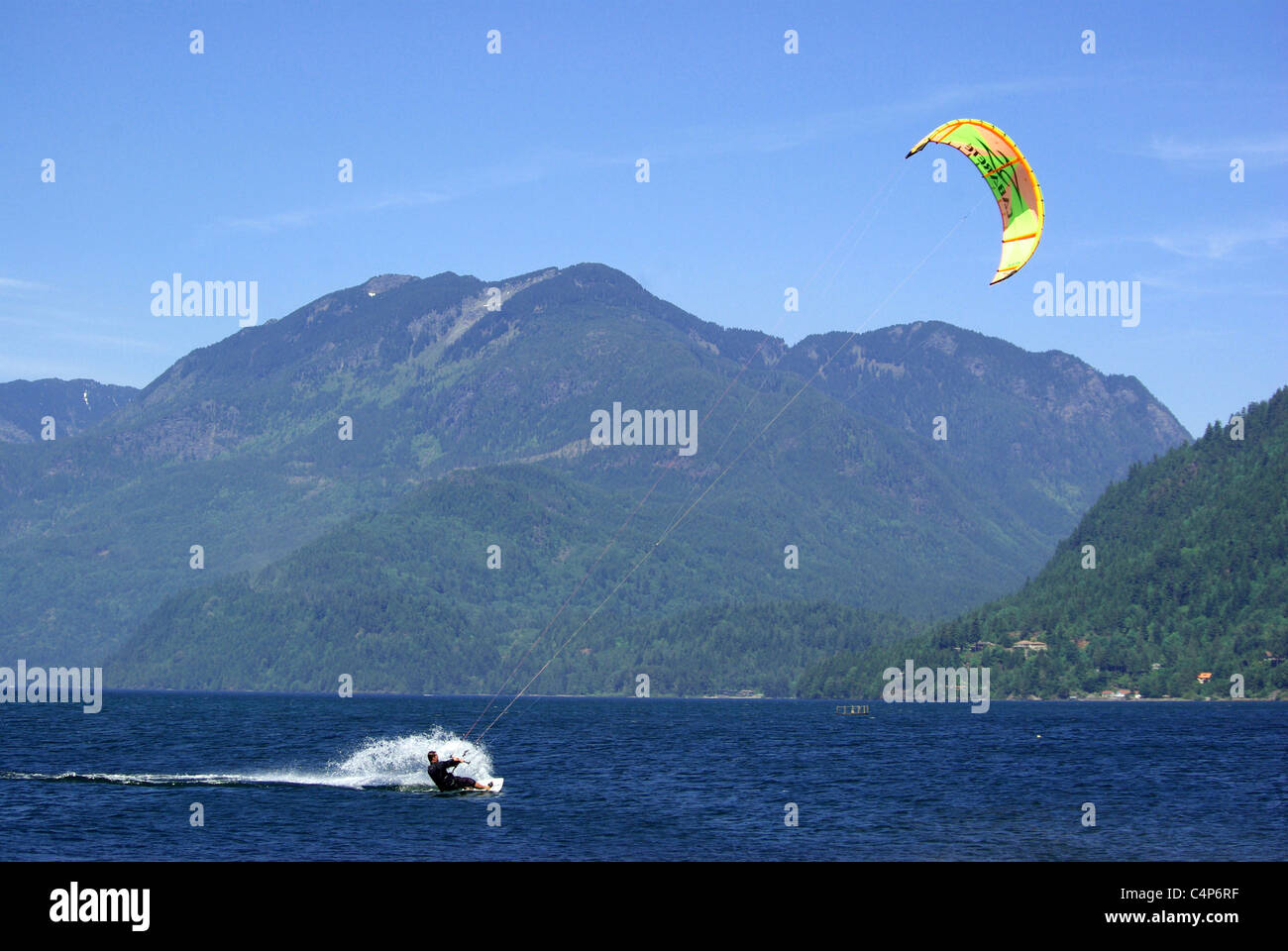 Man in wetsuit making sharp turn while kitesurfing on Harrison Lake in ...