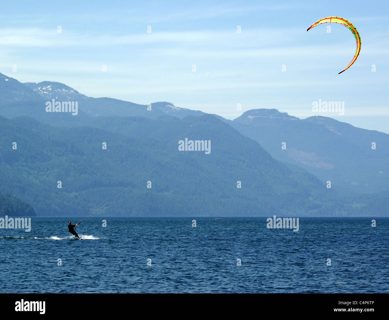 Man in wetsuit kitesurfing in distance on Harrison Lake in B.C., Canada ...