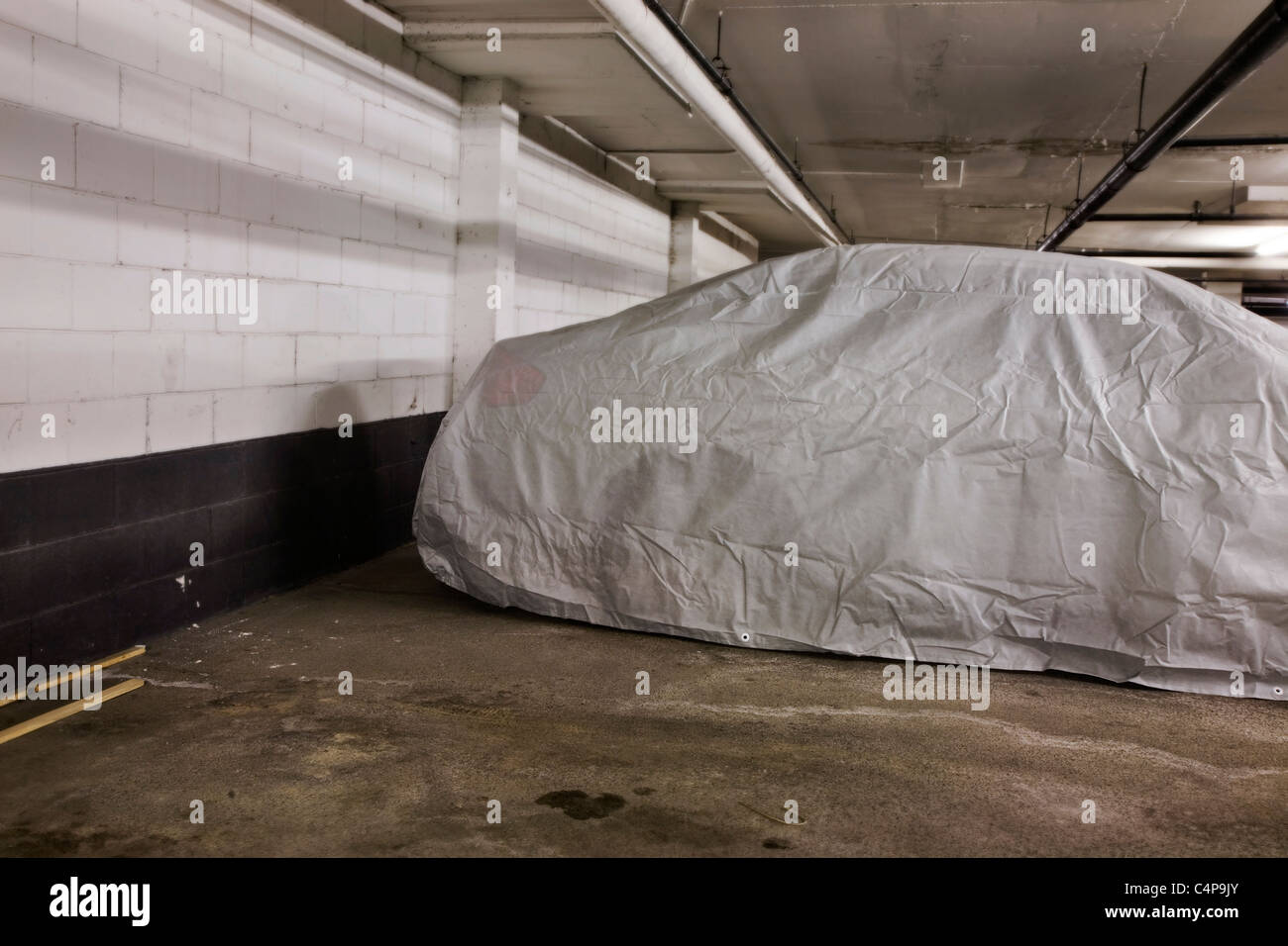 Covered car in underground garage Stock Photo - Alamy