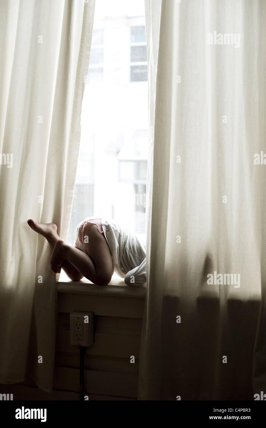Two-year-old girl crawling in diapers on window sill Stock Photo - Alamy