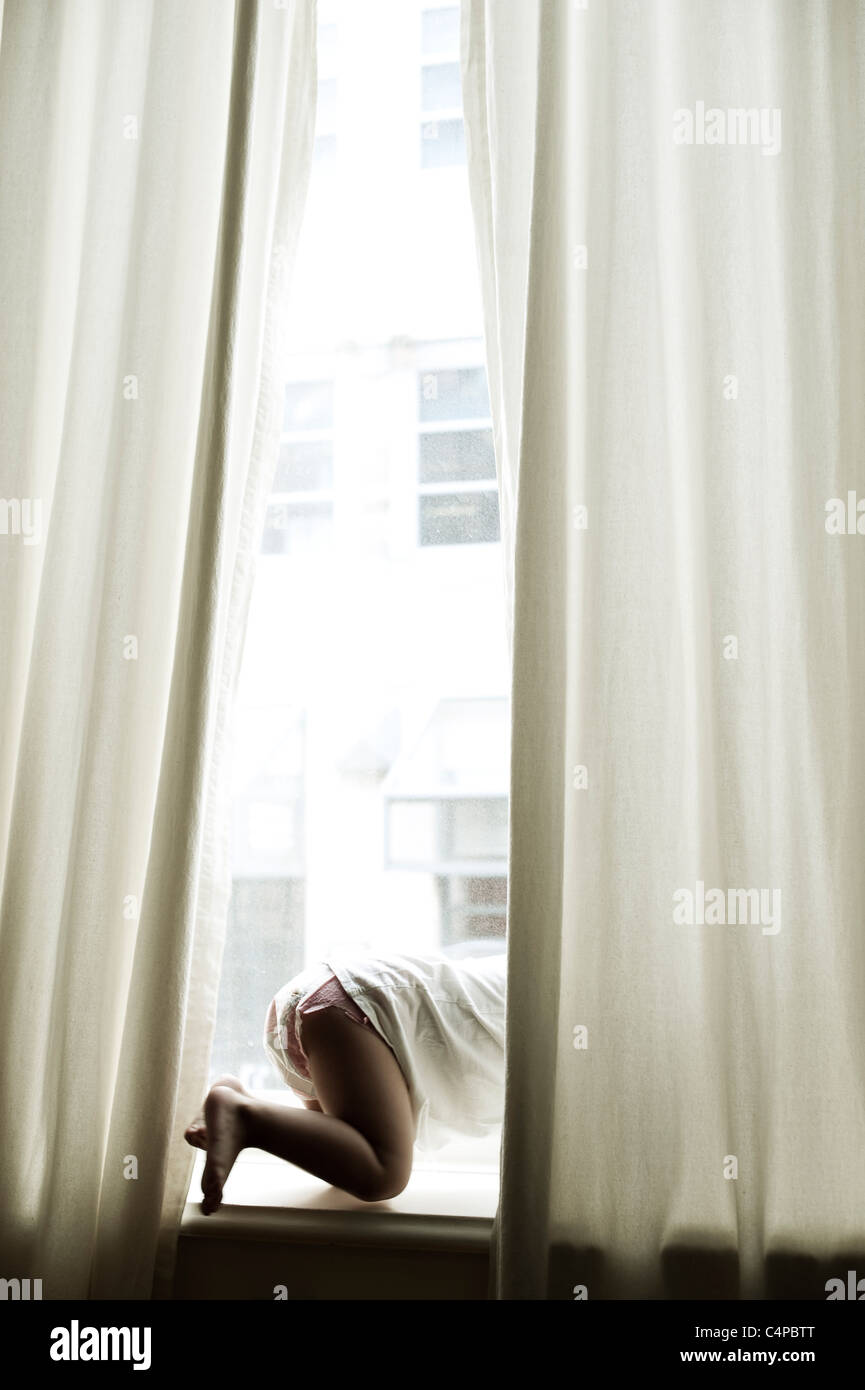 Two-year-old girl crawling in diapers on window sill Stock Photo - Alamy