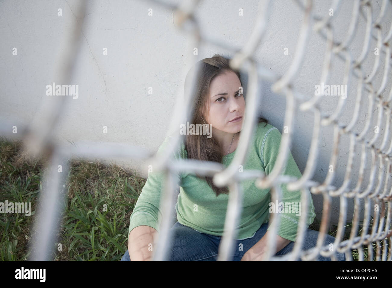 Young woman behind a chain-link fence Stock Photo - Alamy