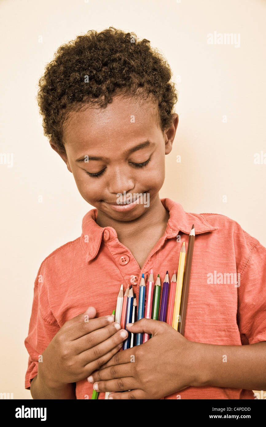 Young boy holding coloured pencils Stock Photo - Alamy