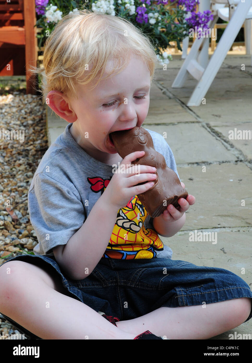 Three and a half year old Caucasian English boy biting into chocolate ...