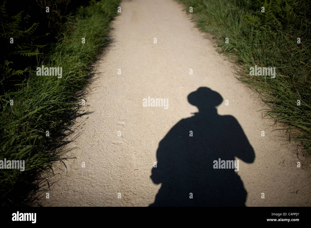 The shadow of a pilgrim is cast as he walks in a earth track in the ...