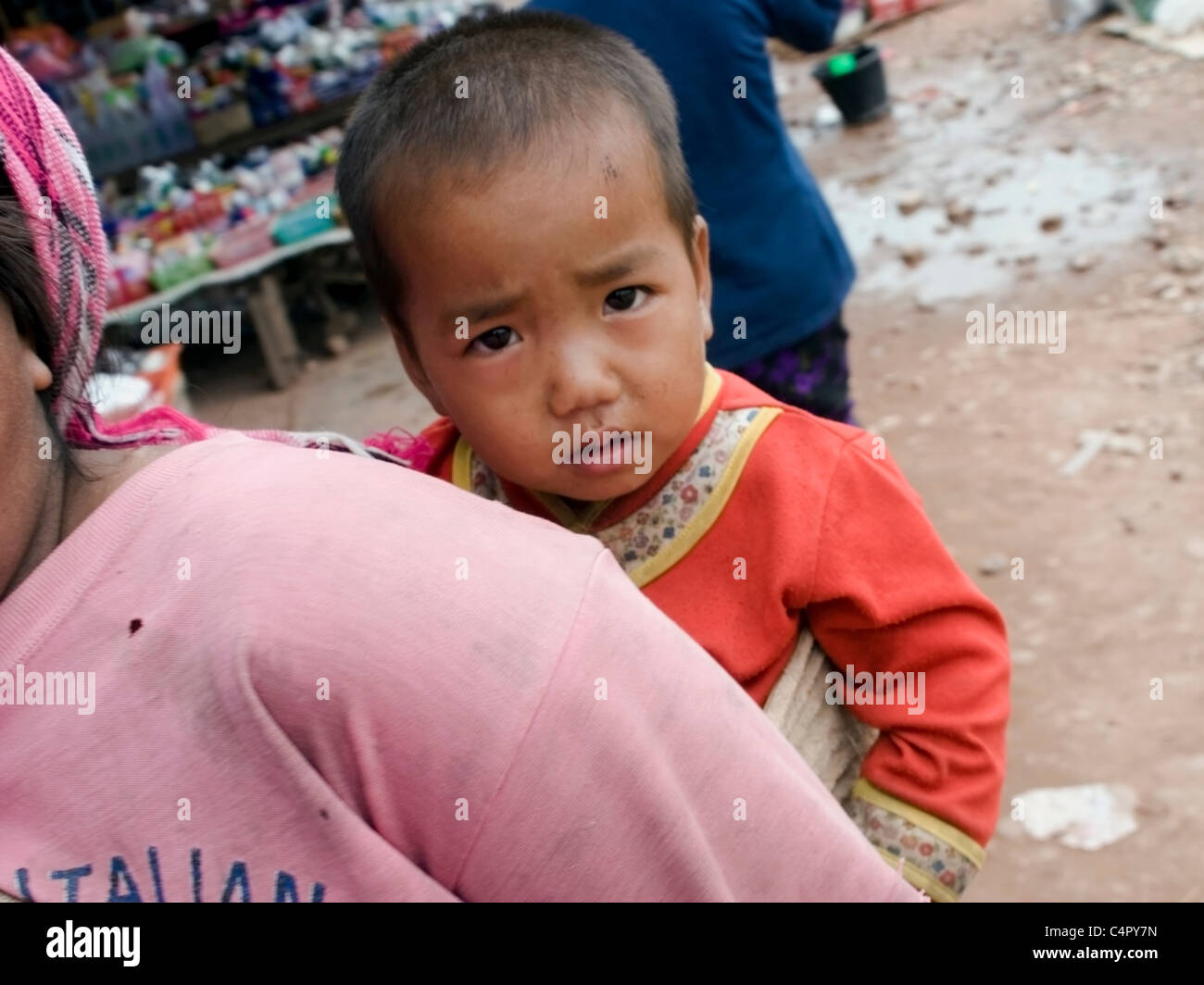 An ethnic hill tribe woman living in poverty is carrying her young boy ...