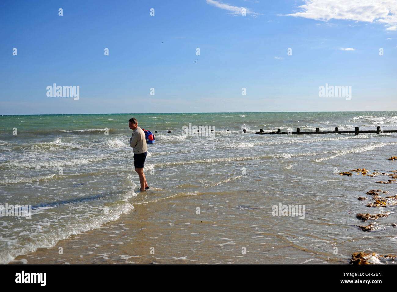 A man takes a paddle at dusk at Ferring beach near Worthing West Sussex ...