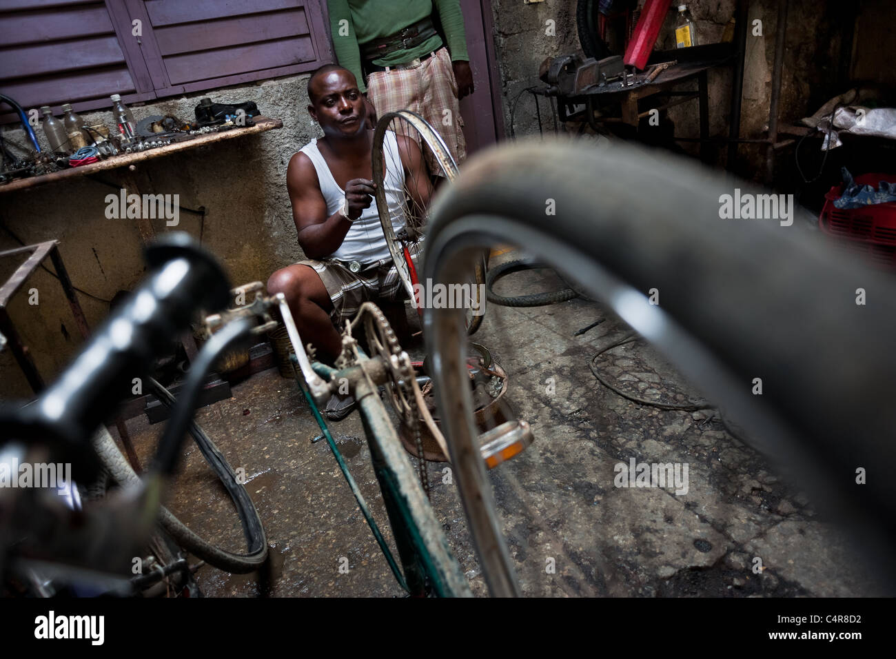 A Cuban service man fixes a bike wheel in the bicycle repair shop in ...