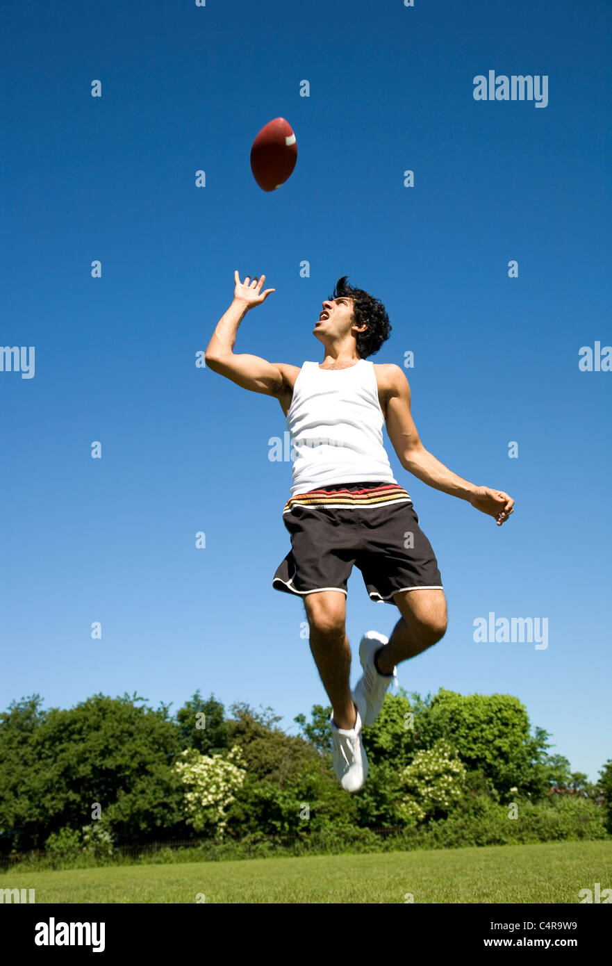 Man jumping playing with oval ball in park Stock Photo - Alamy