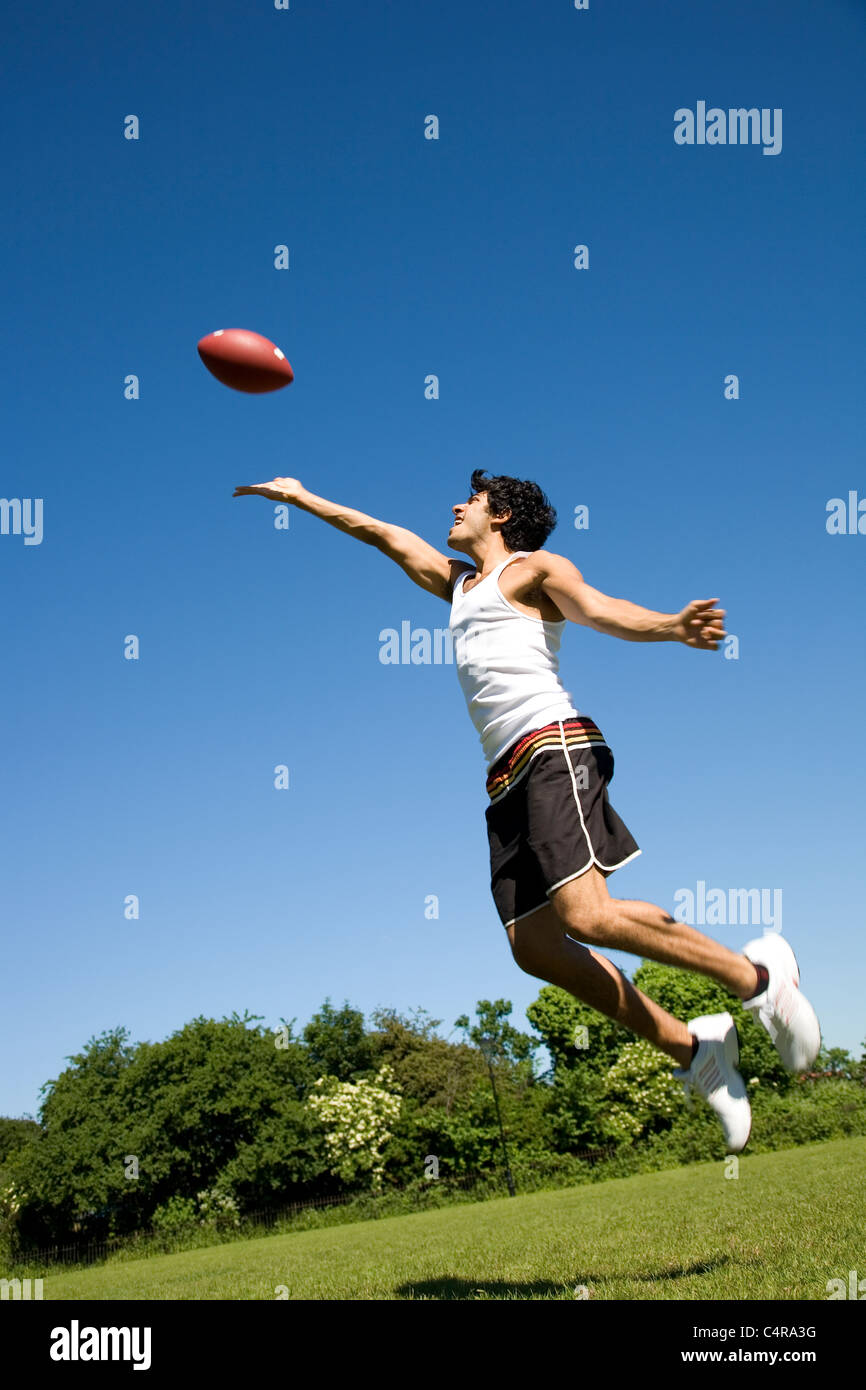 Man jumping playing with oval ball in park Stock Photo - Alamy