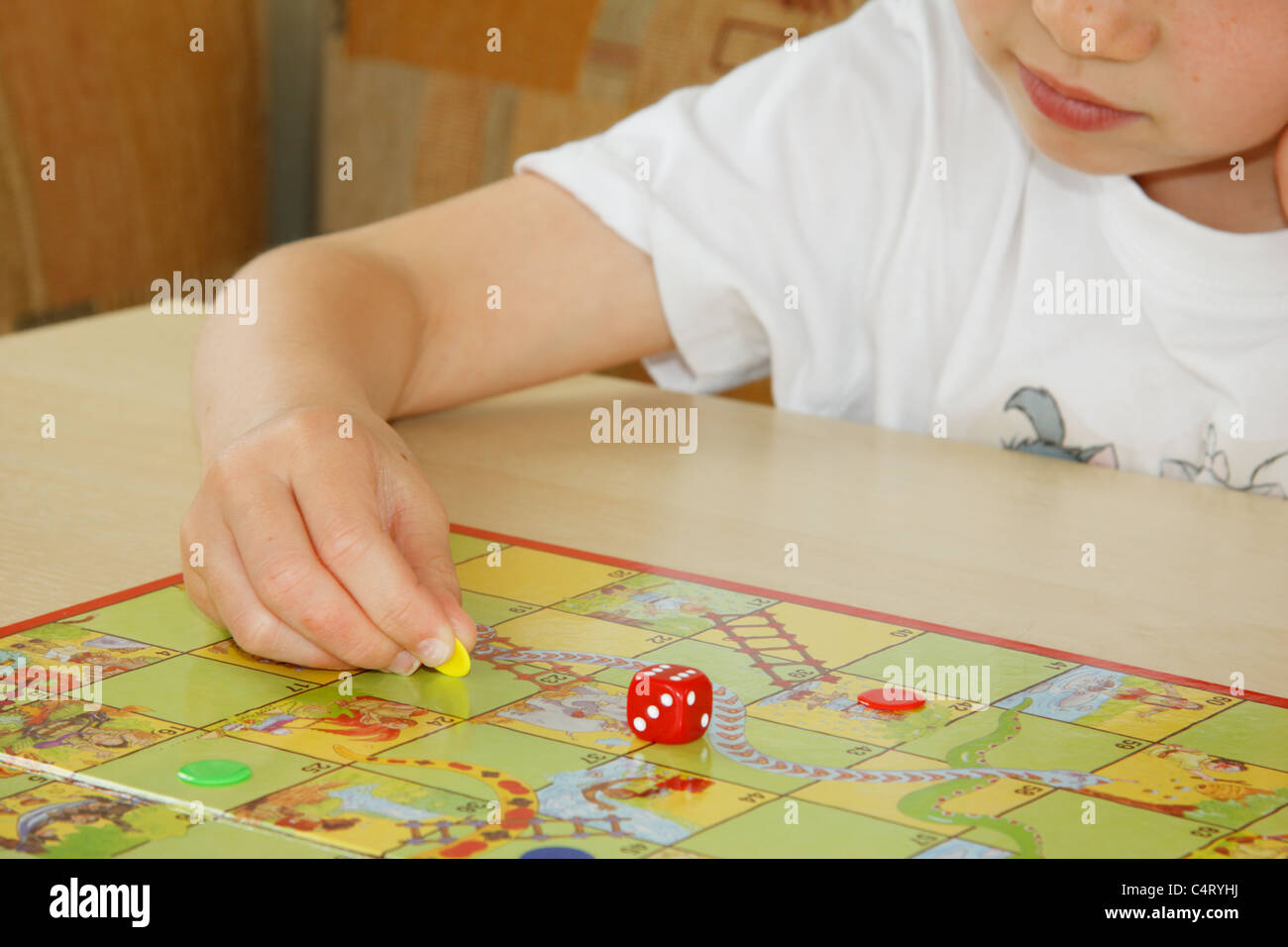 Child's hand moving counter during snakes and ladders game Stock Photo ...