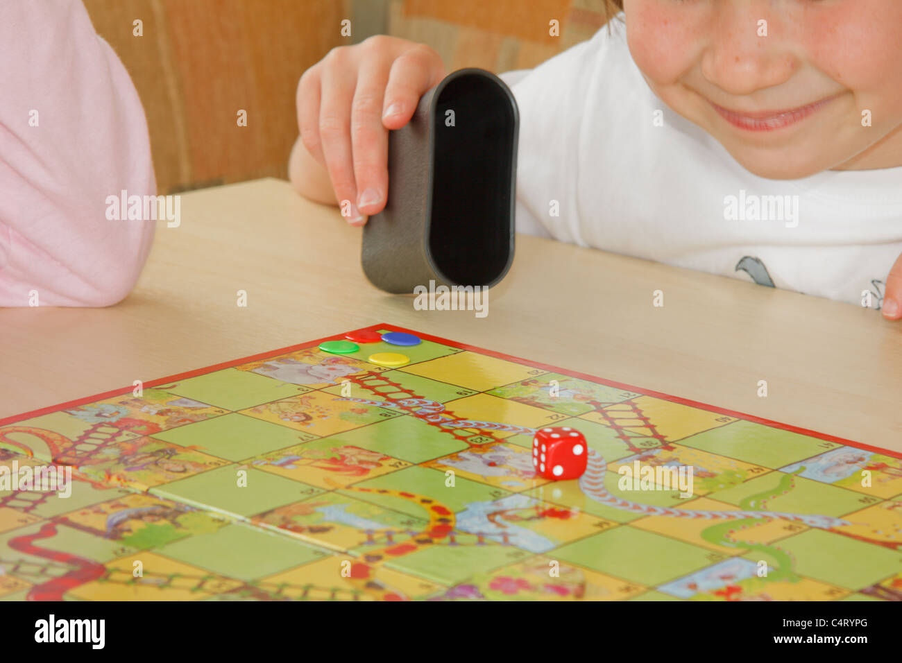 Child throwing a dice during snakes and ladders game Stock Photo - Alamy