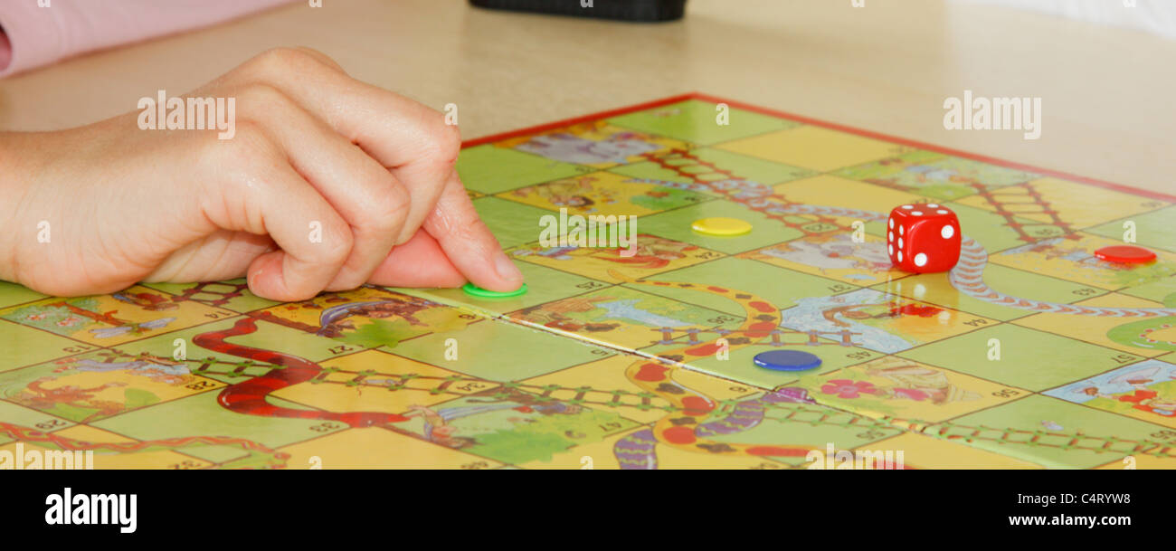 Child's hand moving counter during snakes and ladders game Stock Photo ...