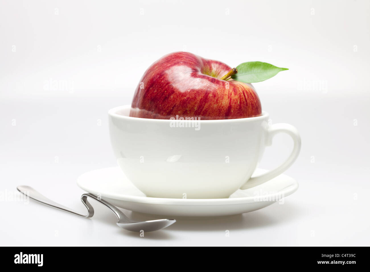 apple in a cup and spoon isolated on white Stock Photo - Alamy