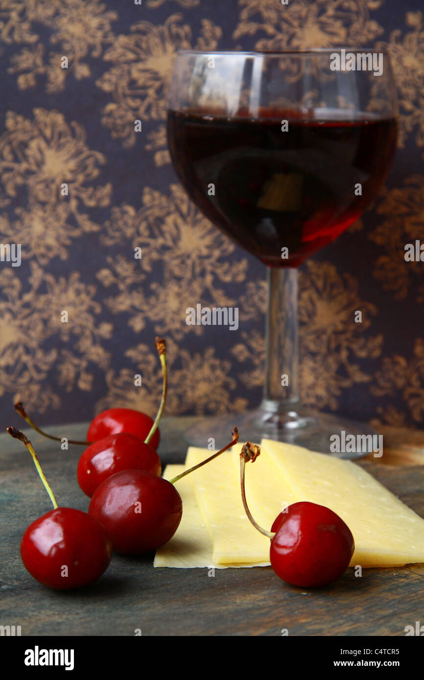 glass of red wine, cheese and cherry - a still life in vintage style ...