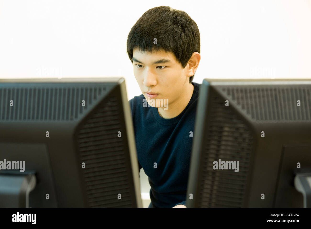 Young man working on computer with two monitors Stock Photo - Alamy