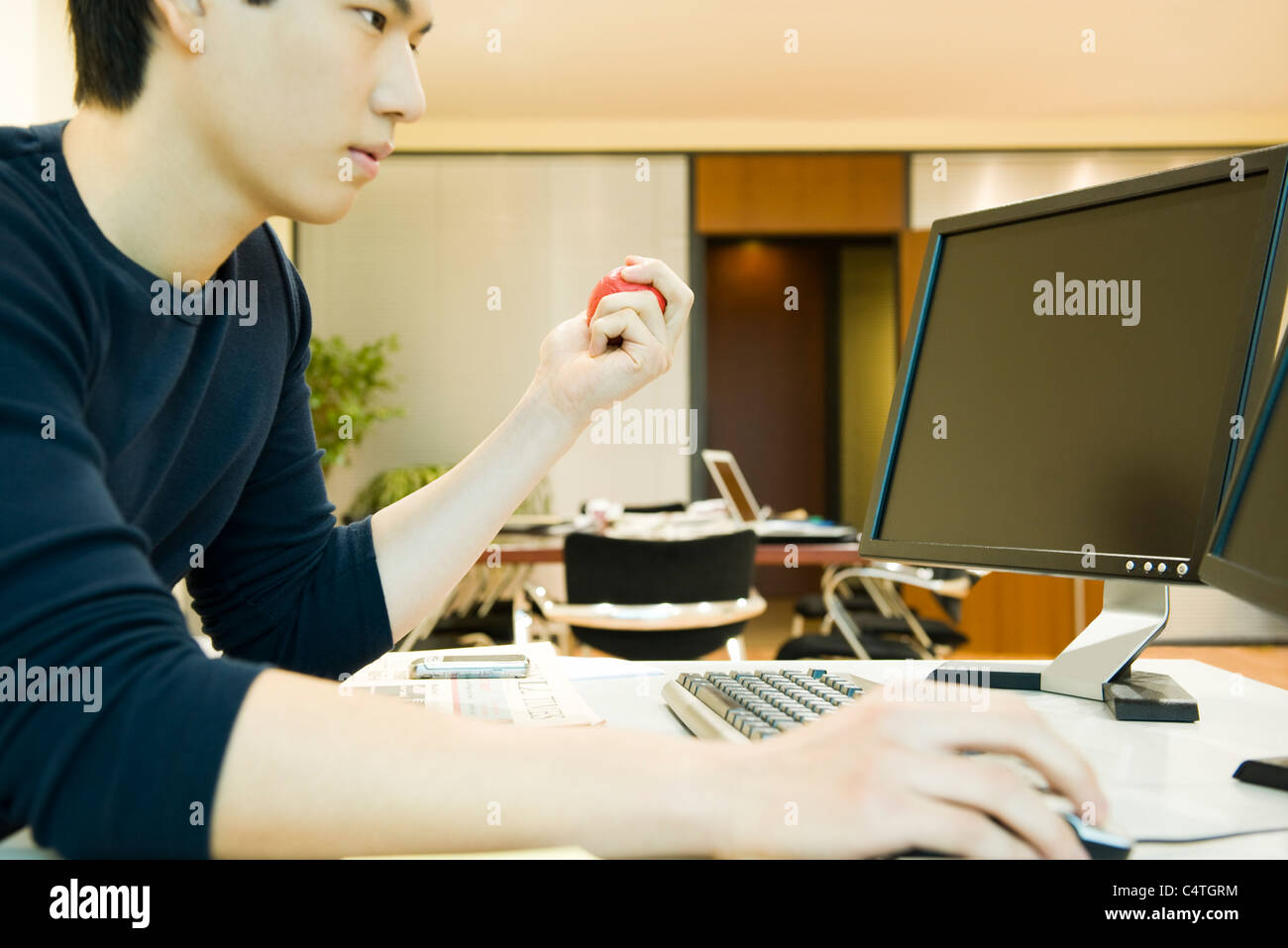 Office worker using computer, squeezing stress ball with one hand Stock ...