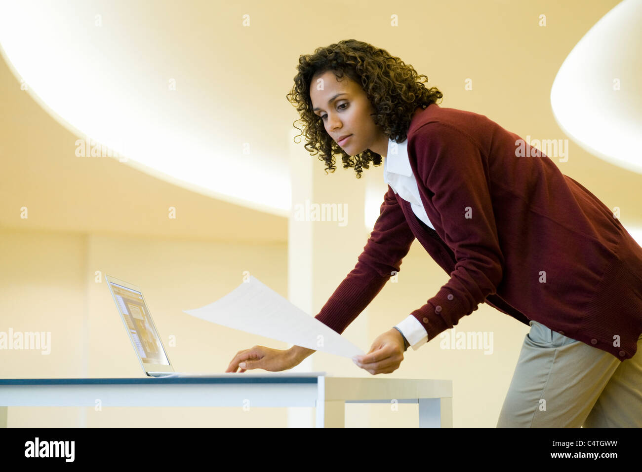 Businesswoman using laptop computer and looking at document Stock Photo ...