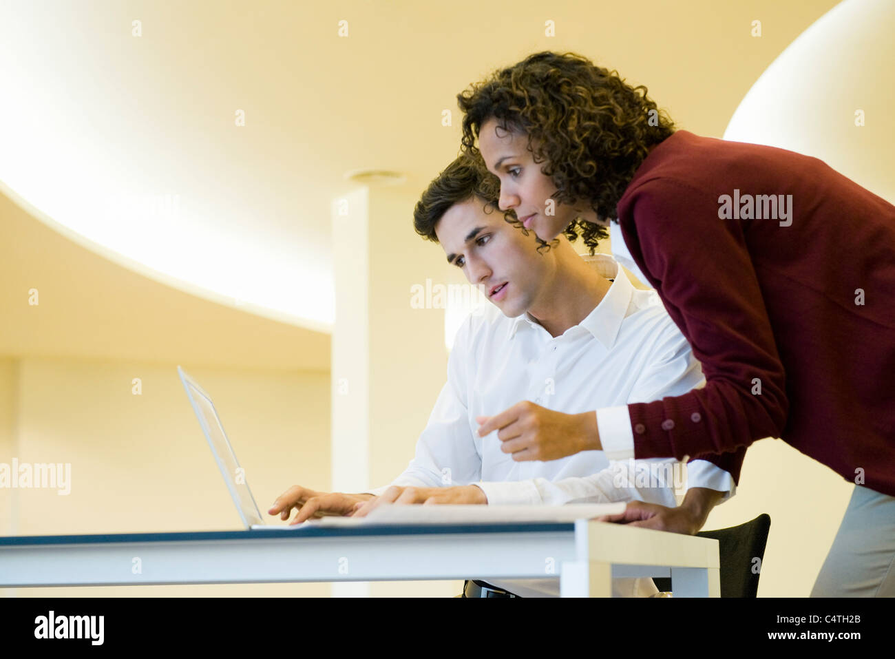 Colleagues using laptop computer together Stock Photo - Alamy