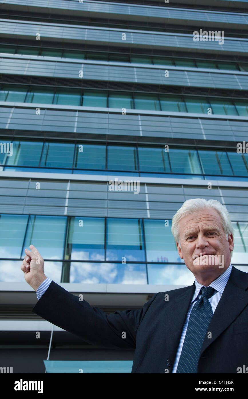 Executive pointing at office building, portrait Stock Photo - Alamy