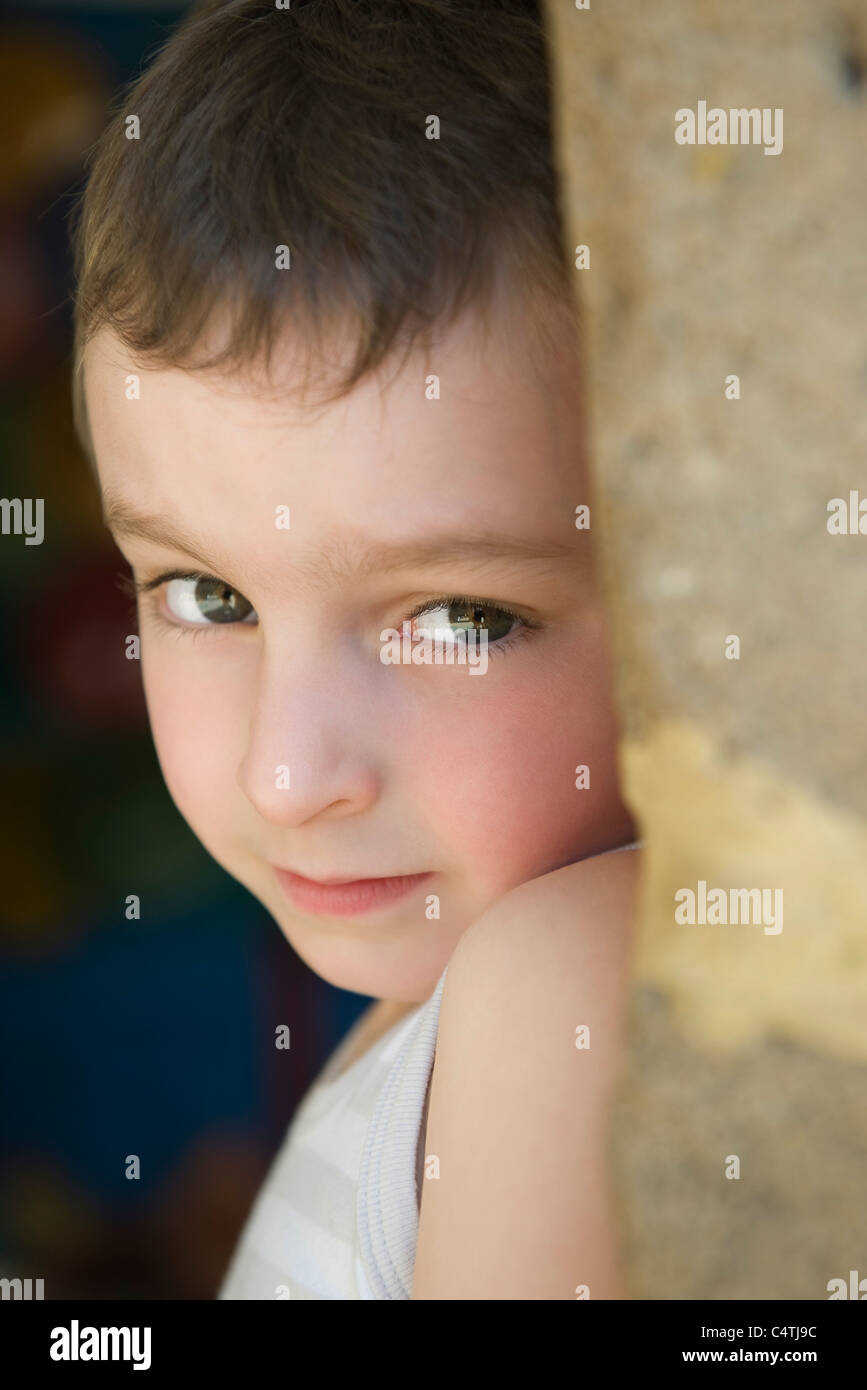 Little boy leaning against tree trunk, portrait Stock Photo - Alamy