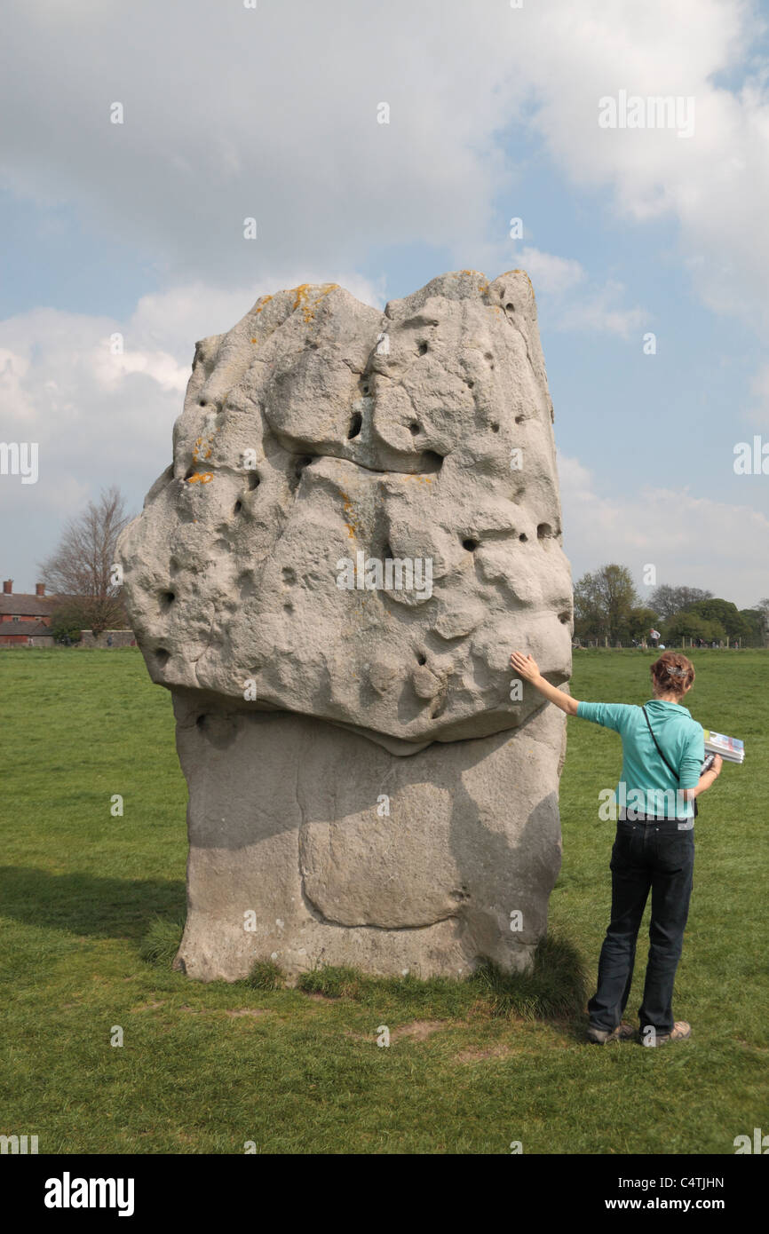 A woman standing beside a massive sarsen standing stone, part of the ...